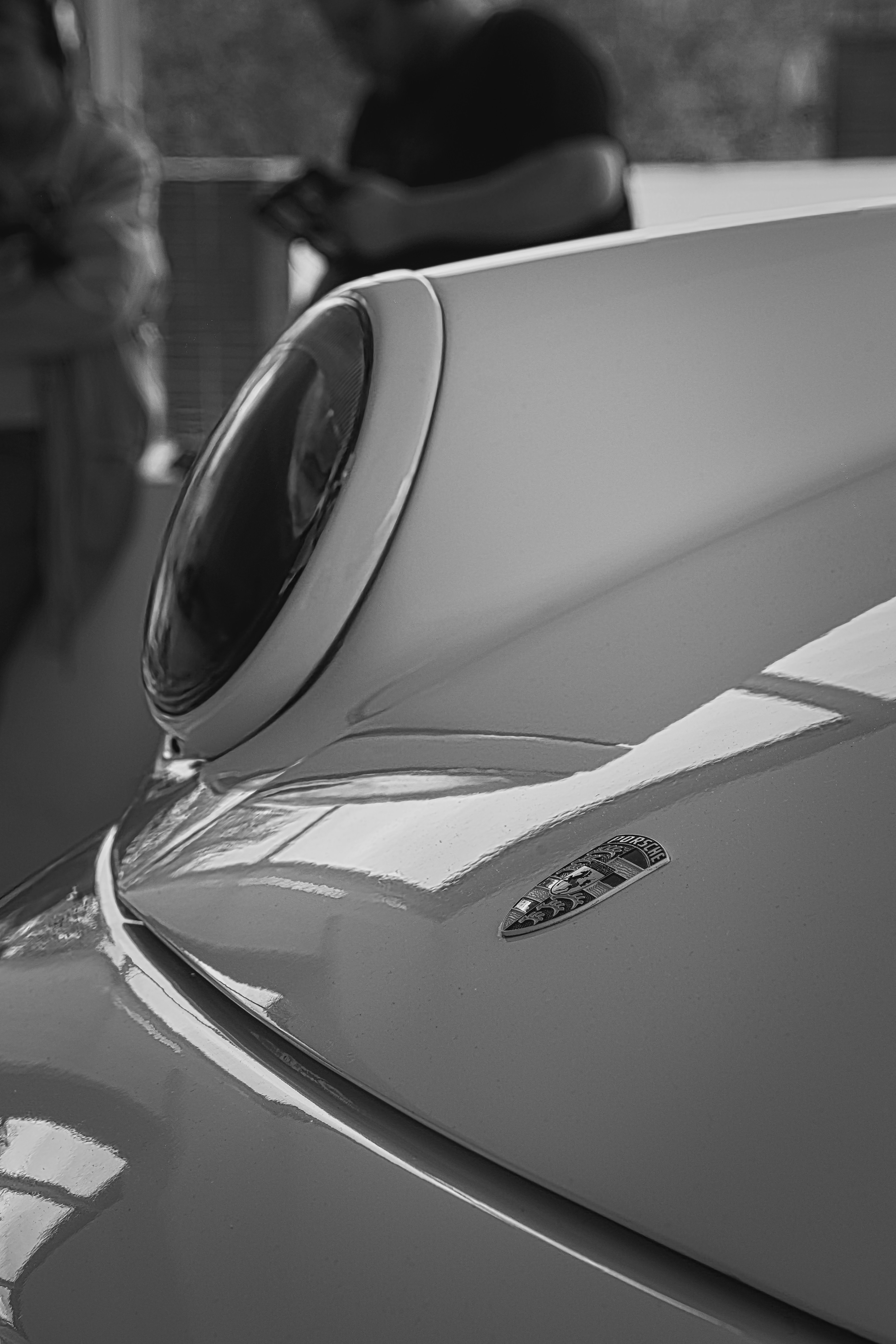 Chrome Curves: The Porsche Hood Emblem and Headlight in Quiet Focus