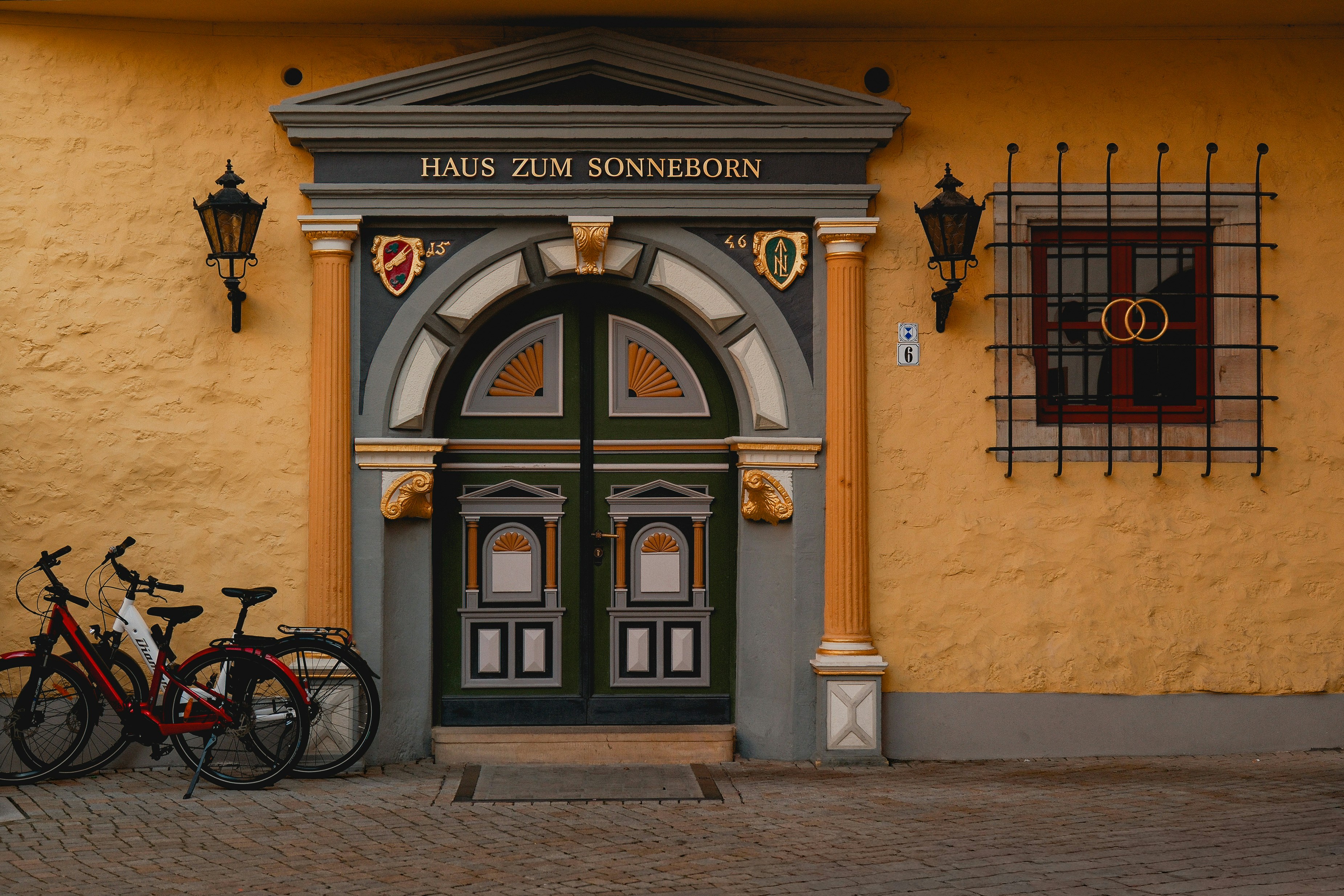 Ornate doorway of Haus Zum Sonneborn on sunlit ochre wall