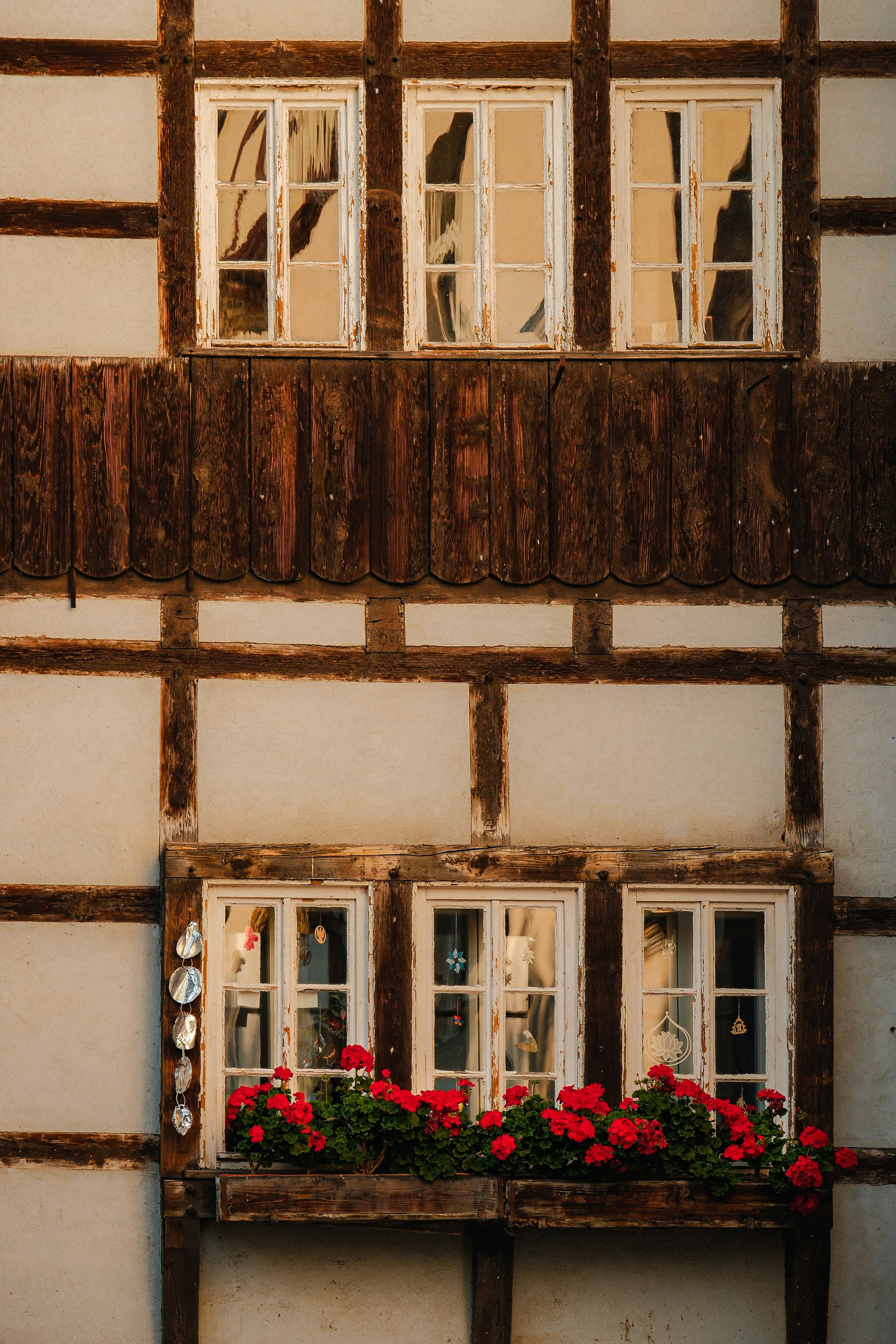 Balcony of Crimson Blooms over a Timbered Facade