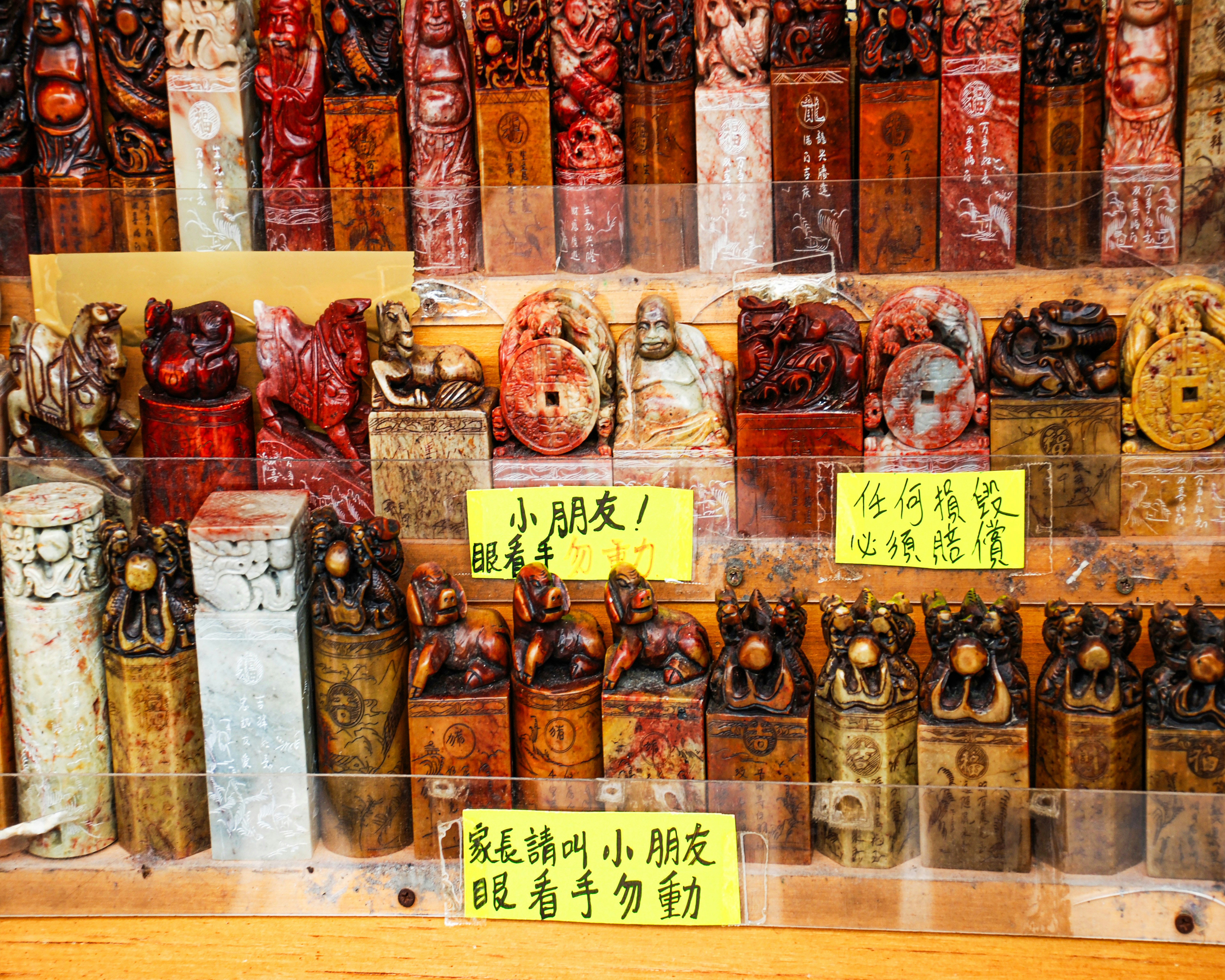 Row of carved figurines on a sunlit storefront shelf