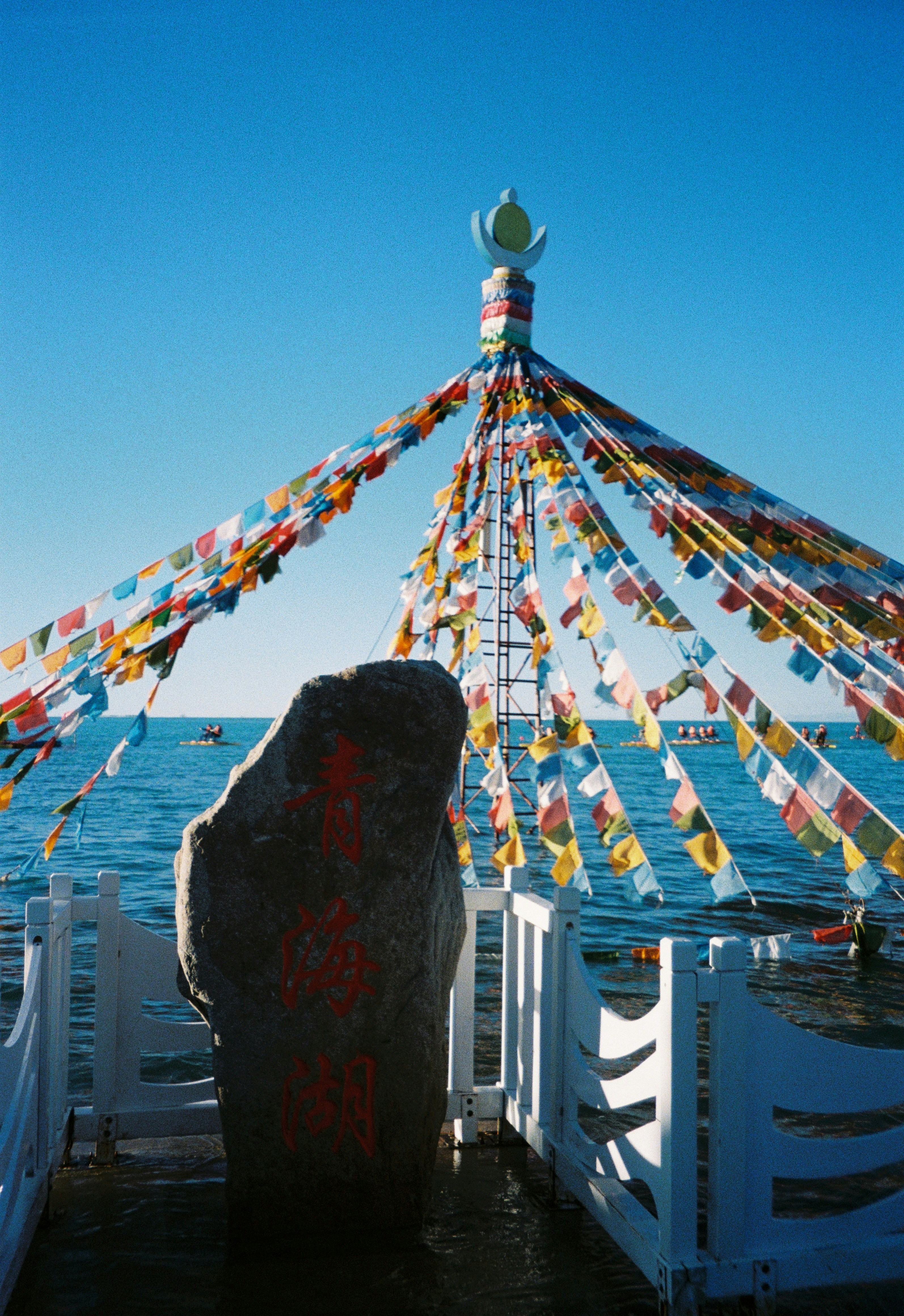 Prayer Flags Crown a Coastal Marker Under a Cerulean Sky