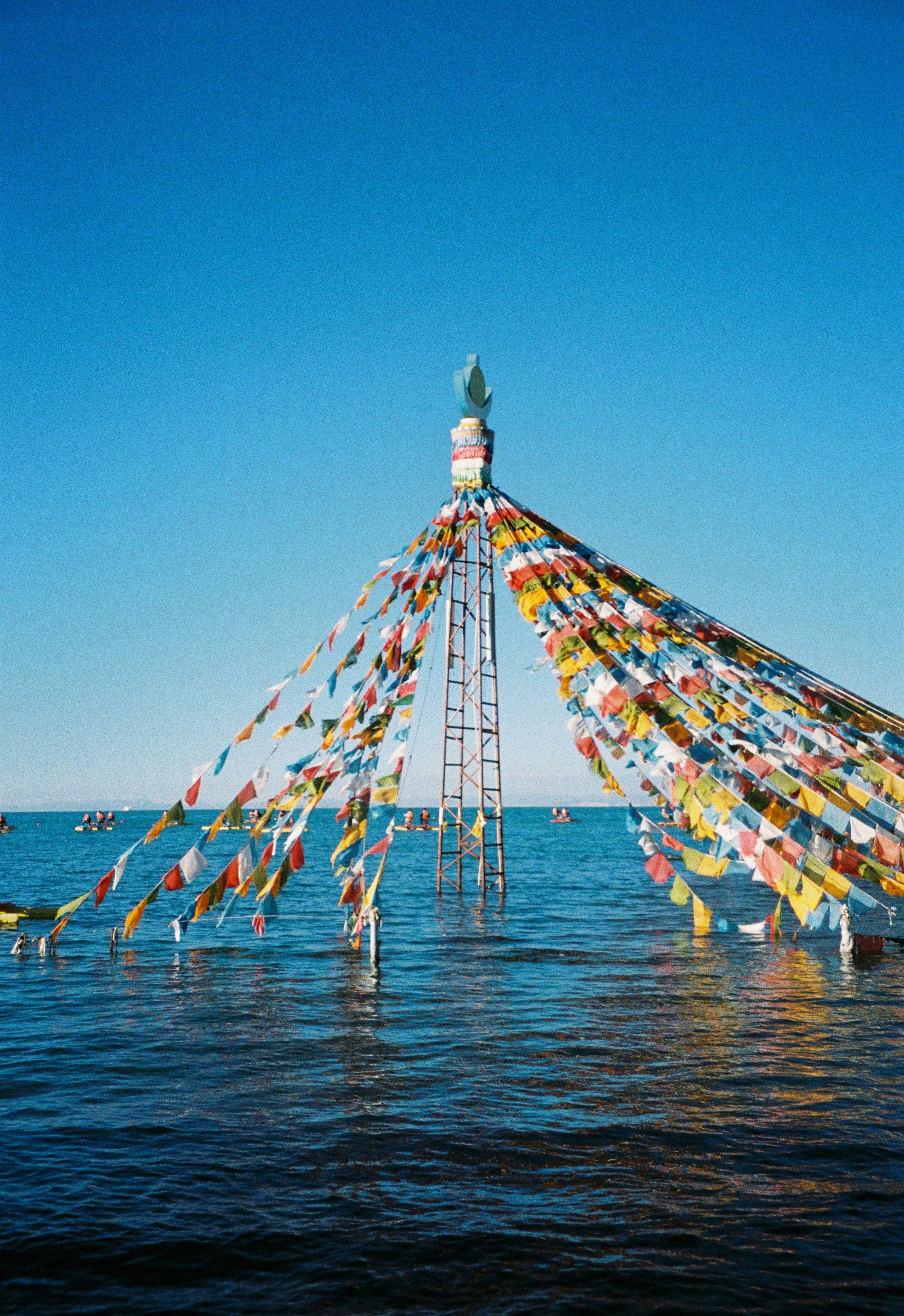 Prismatic prayer flags over calm blue waters