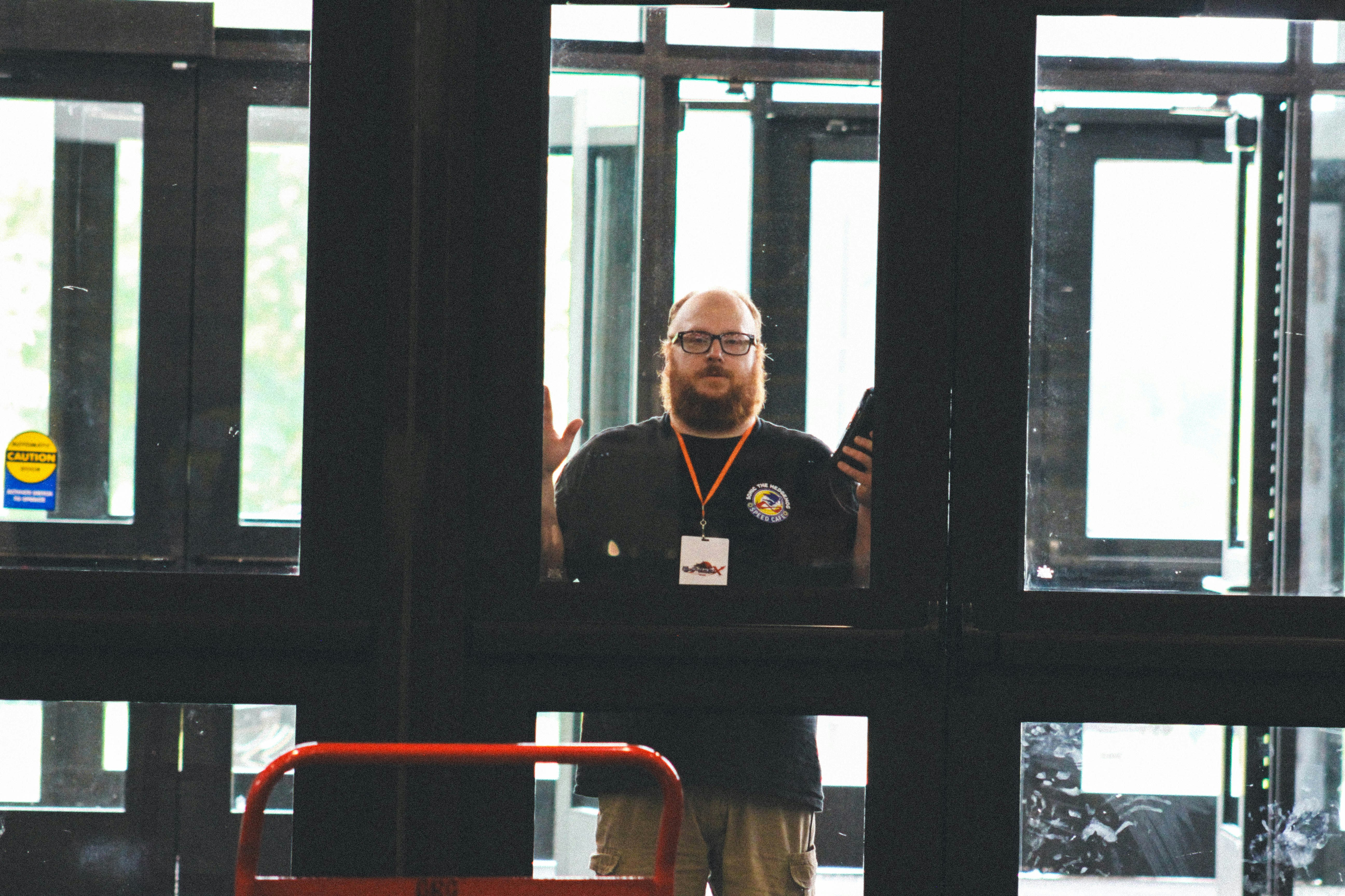 Bearded attendant at a doorway: a welcoming stance framed by glass and shadows