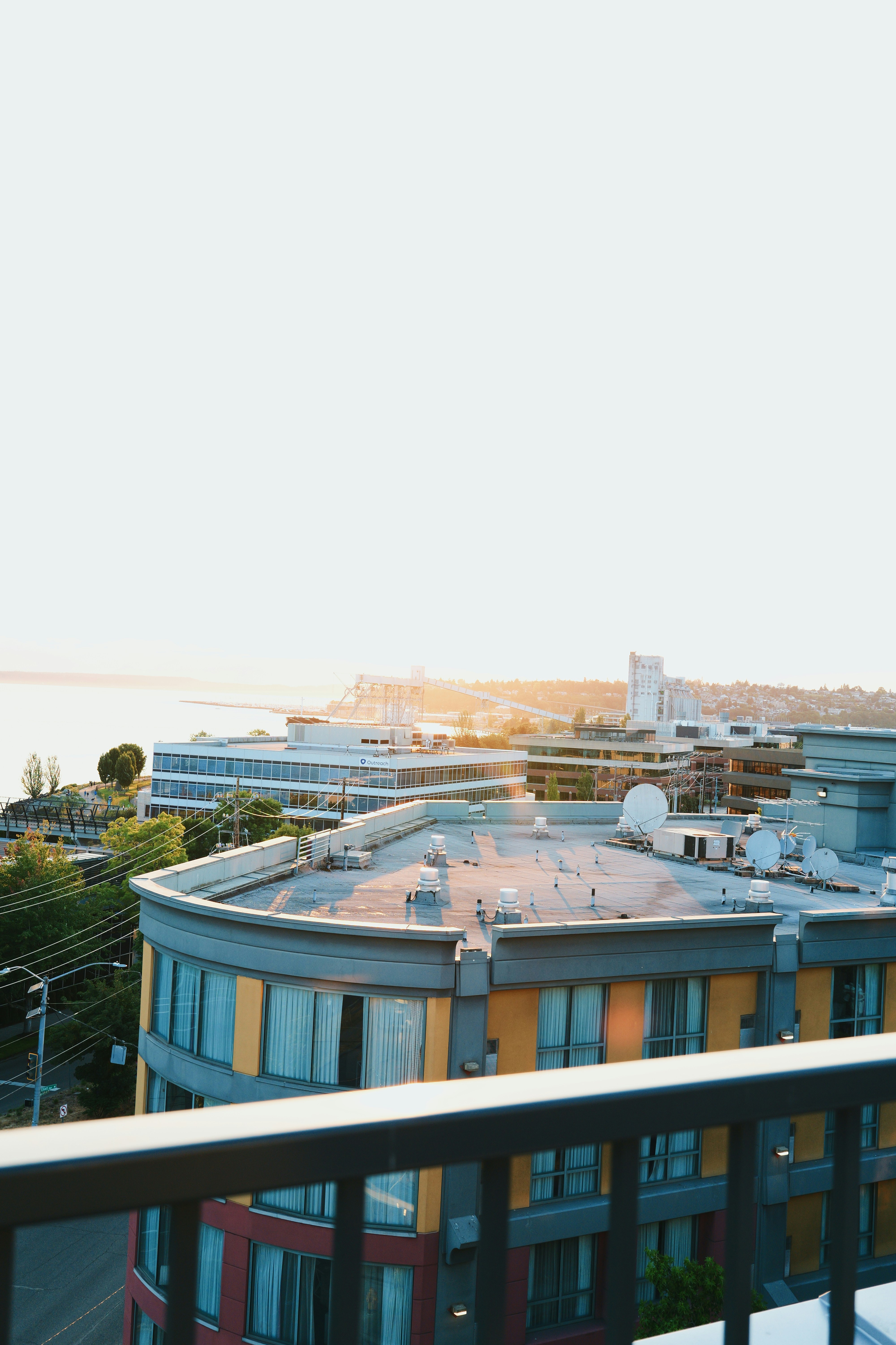 Sunlit Rooftops and Coastal Horizon from a City Balcony