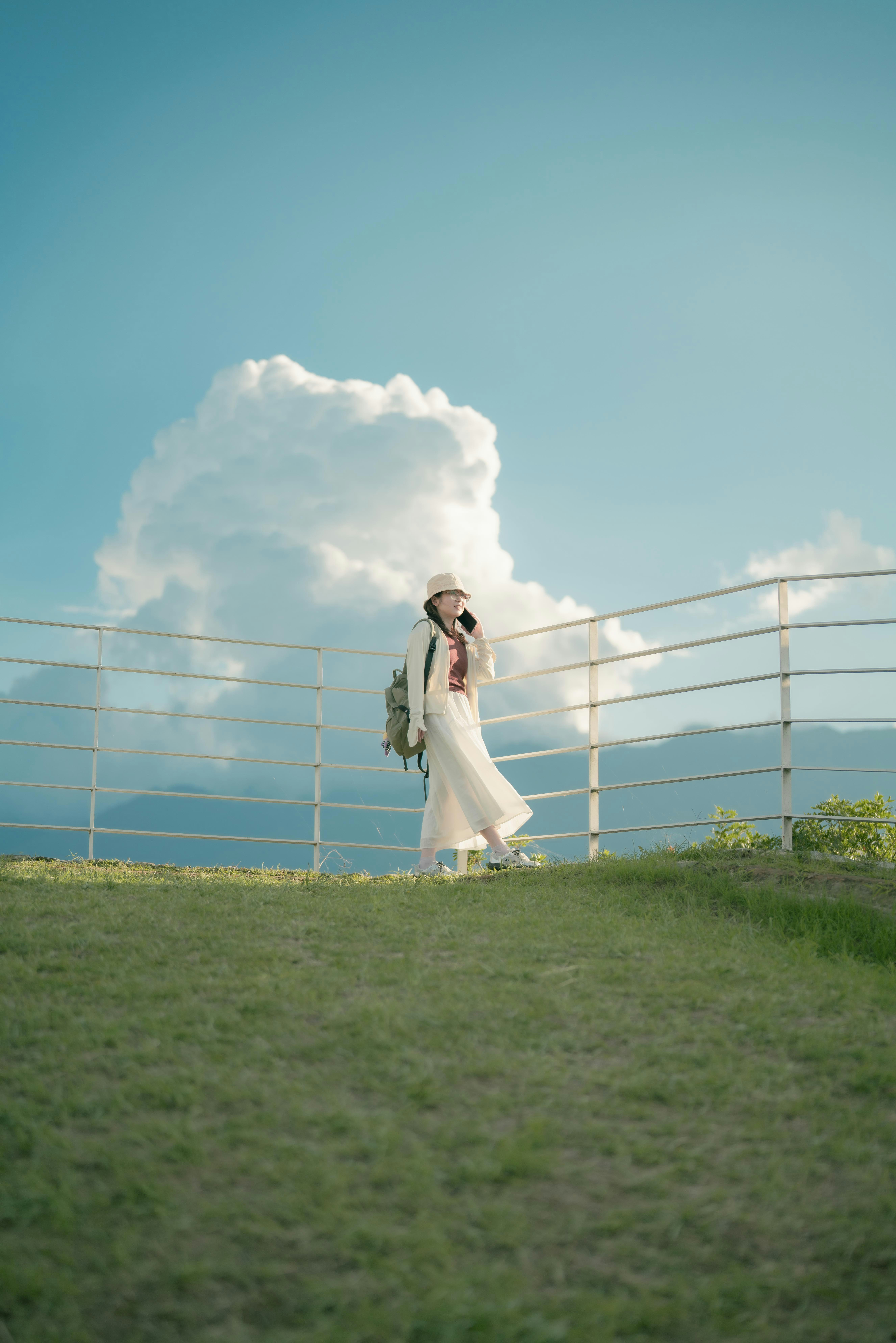 Traveler in a Serene Summit Field under a Sky of Cotton