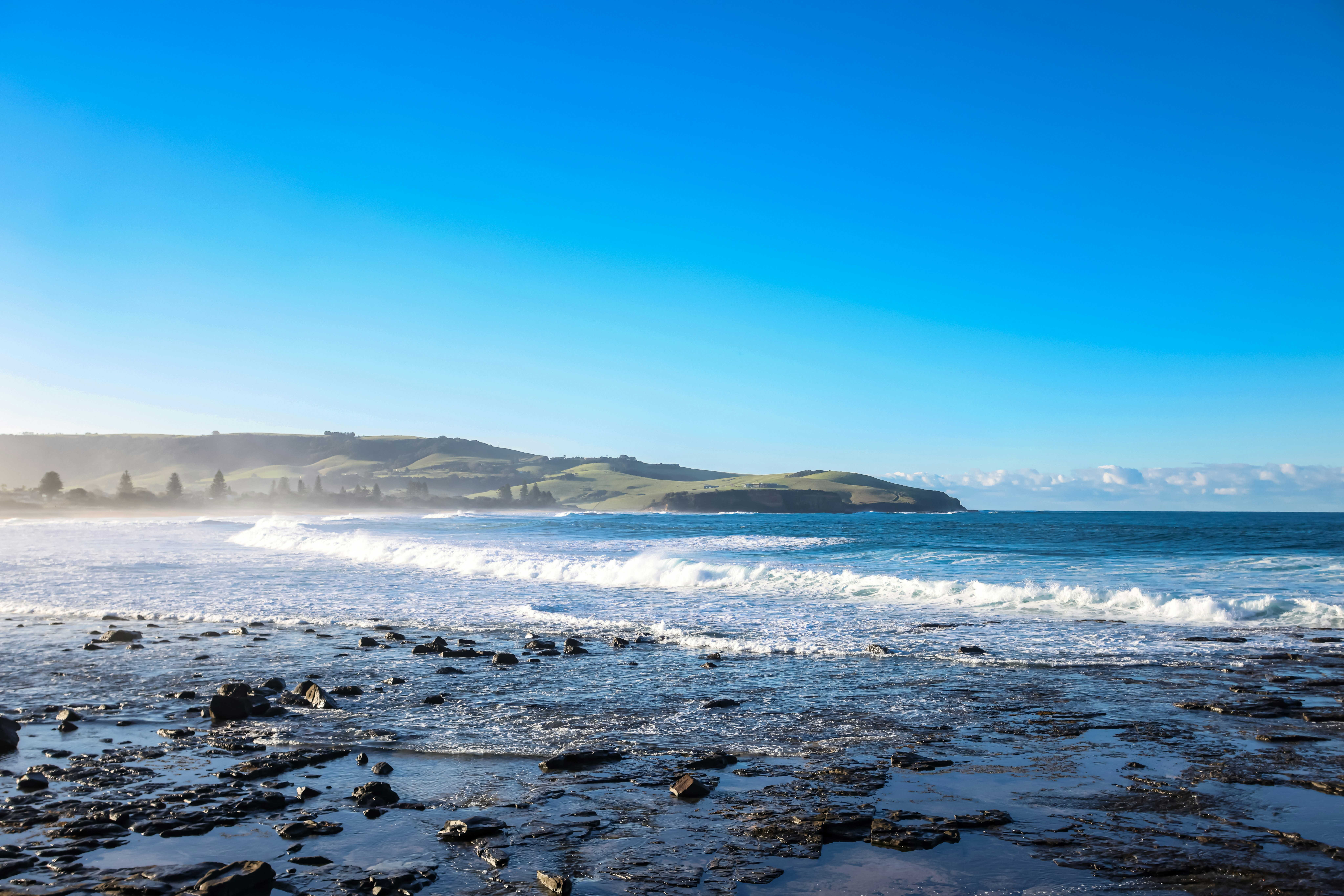 Coastal Horizon: Sunlit Breakers over a Rocky Shore