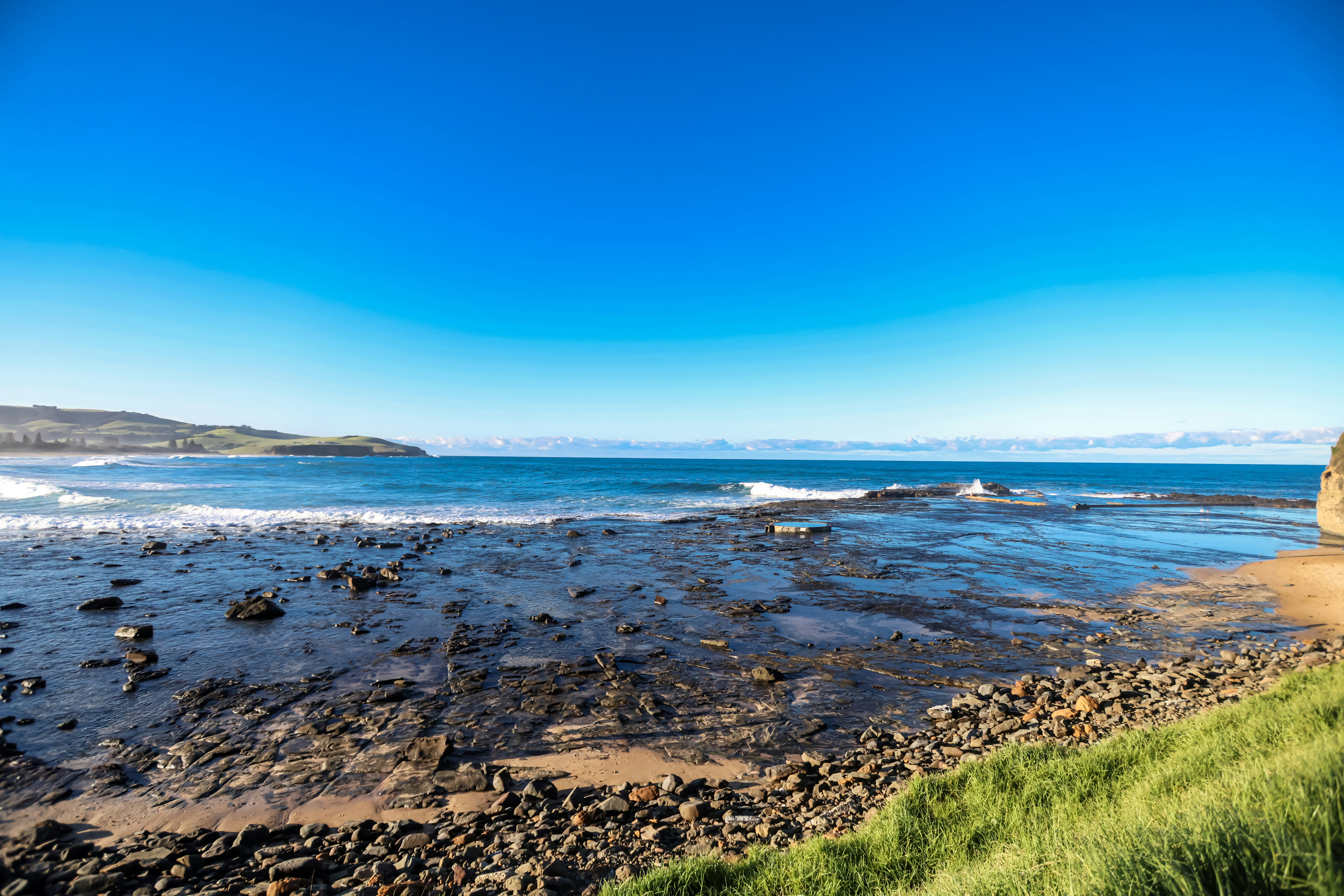Sunlit Coastal Rocks Meet a Wide Horizon under Deep Blue Sky