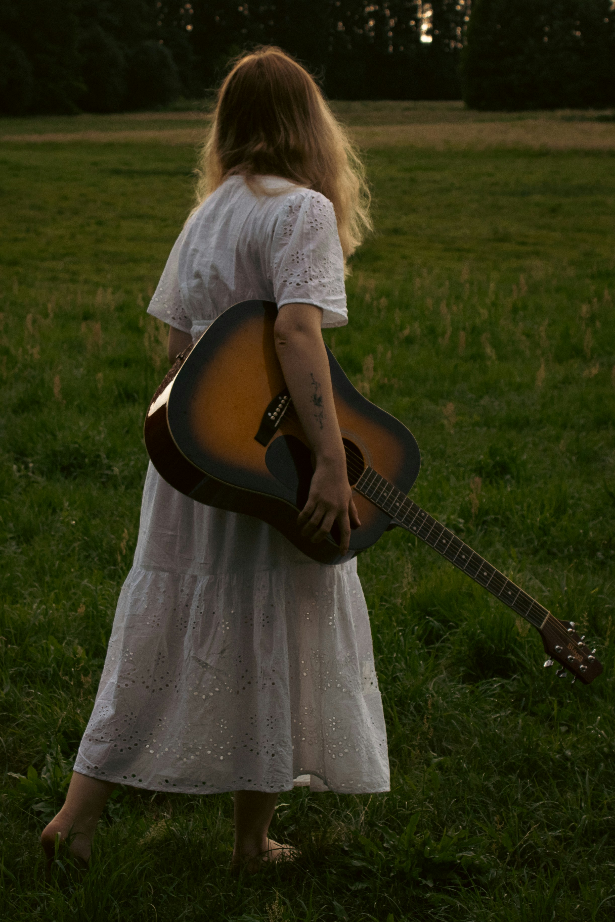 Backlit guitarist in a sunlit meadow