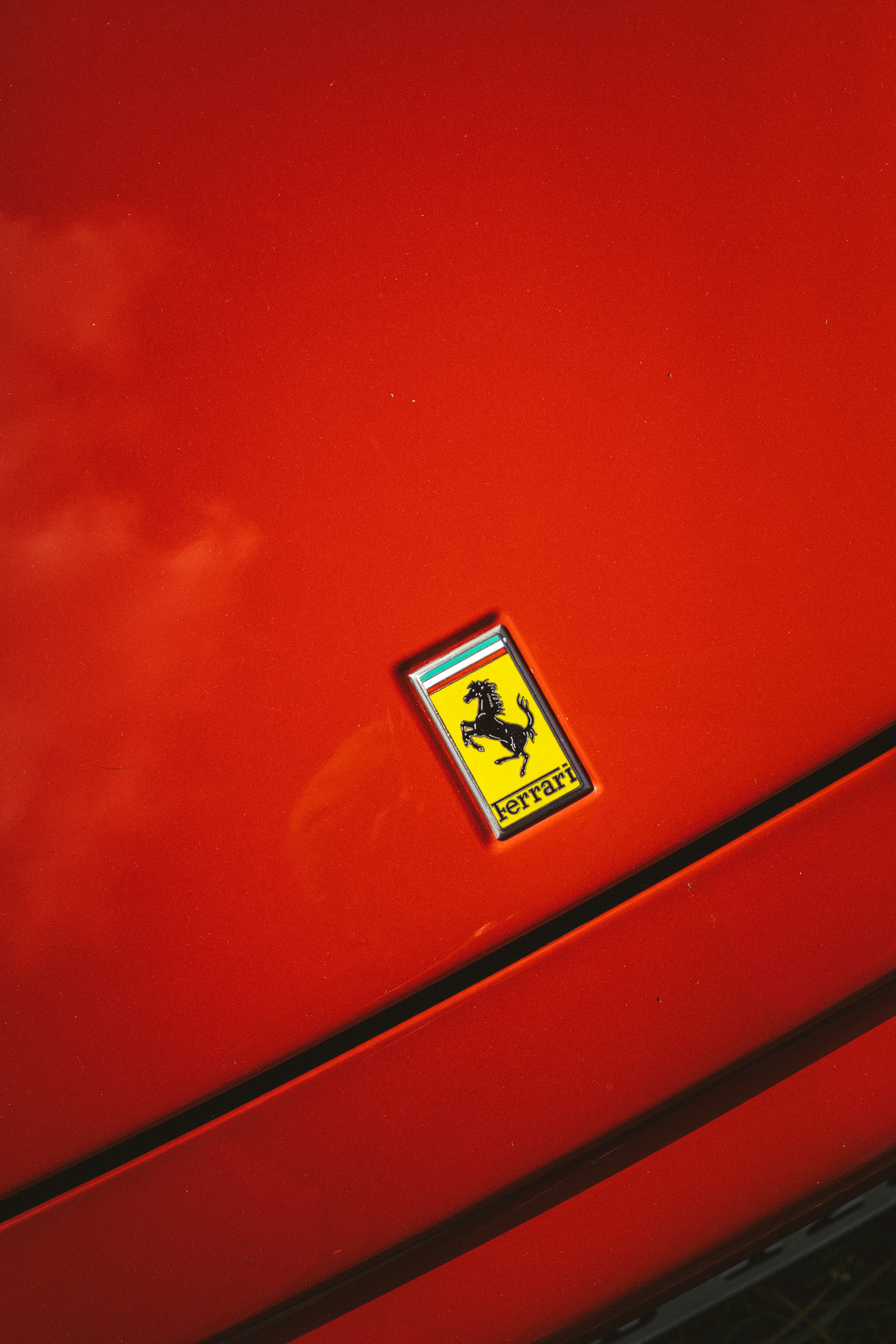 Emblem on a Crimson Curve: Ferrari Badge Adorns a Glossy Red Hood