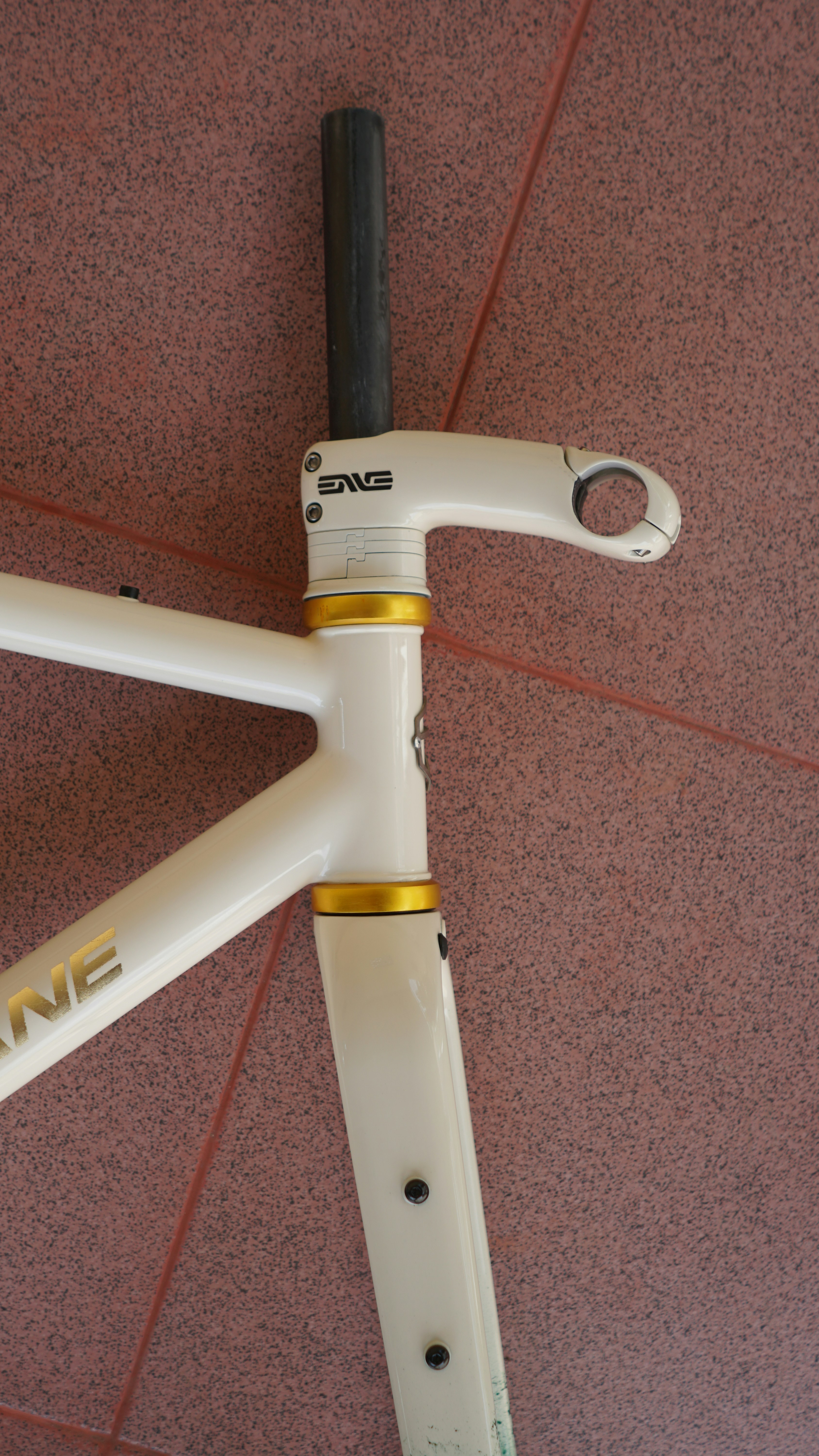 White Bicycle Frame with golden headset against pink terrazzo floor
