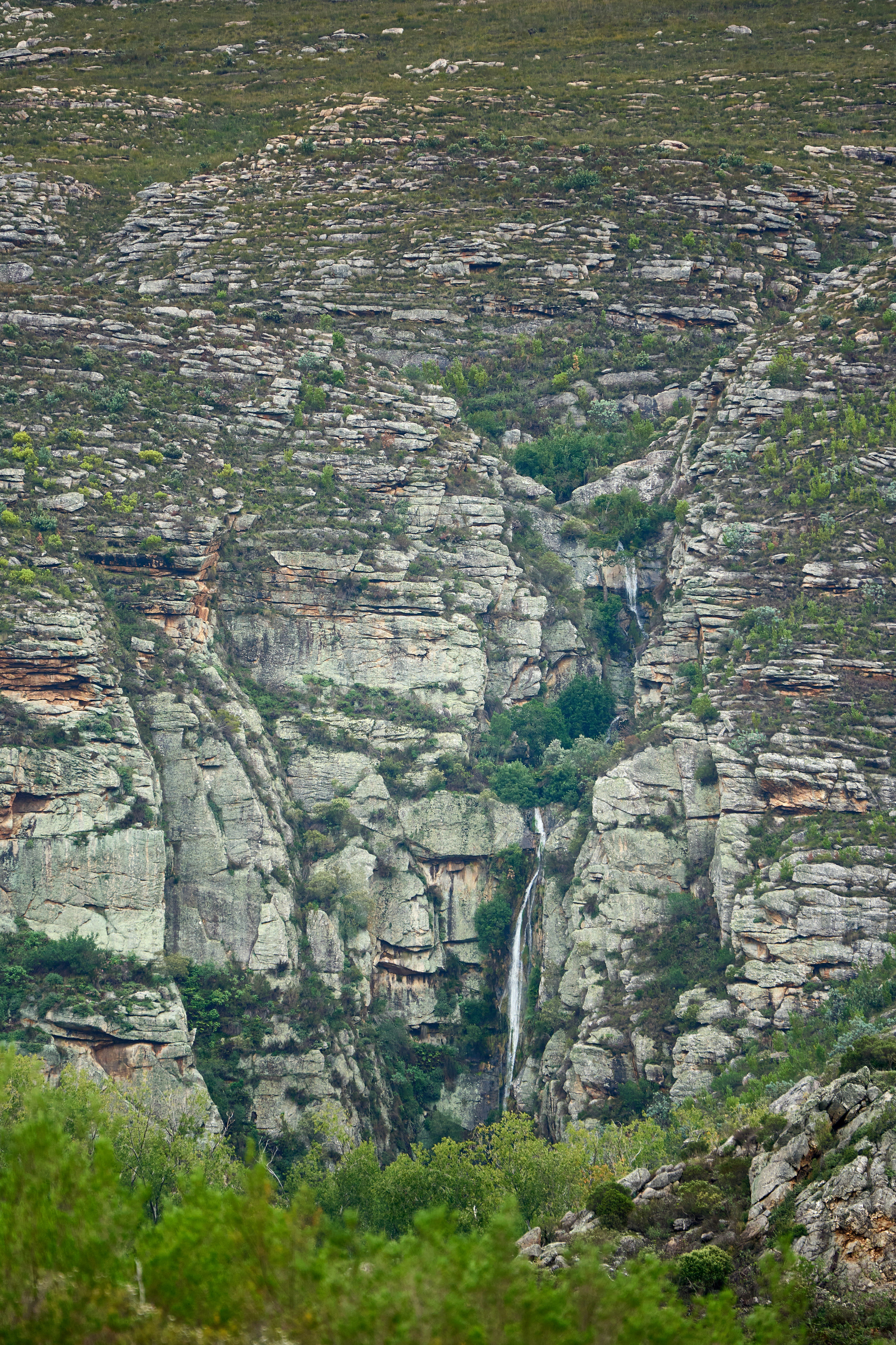 Hidden Cascade Between Weathered Cliffs