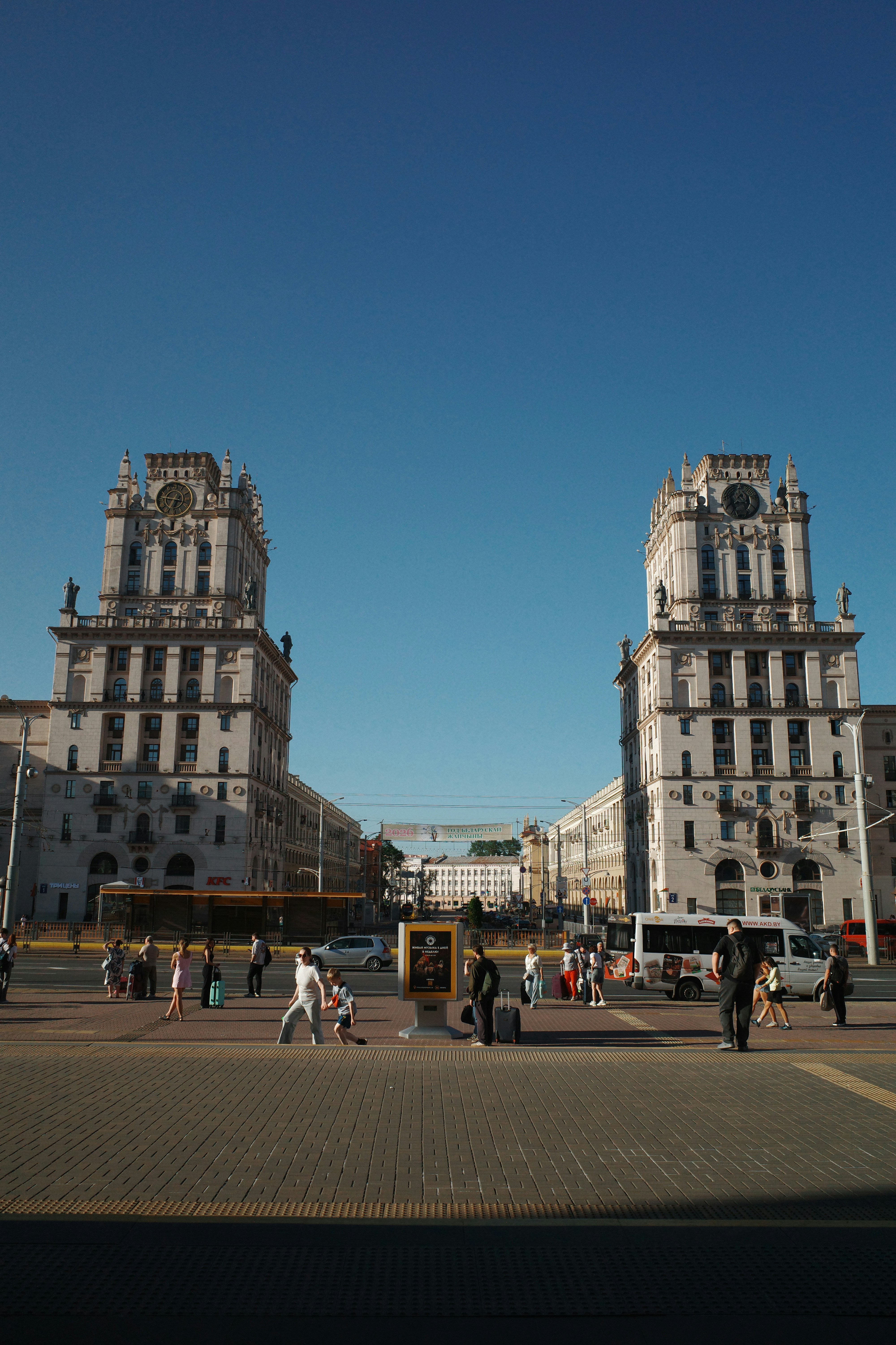 Twin Clock Towers Oversight: City Square Under a Clear Sky
