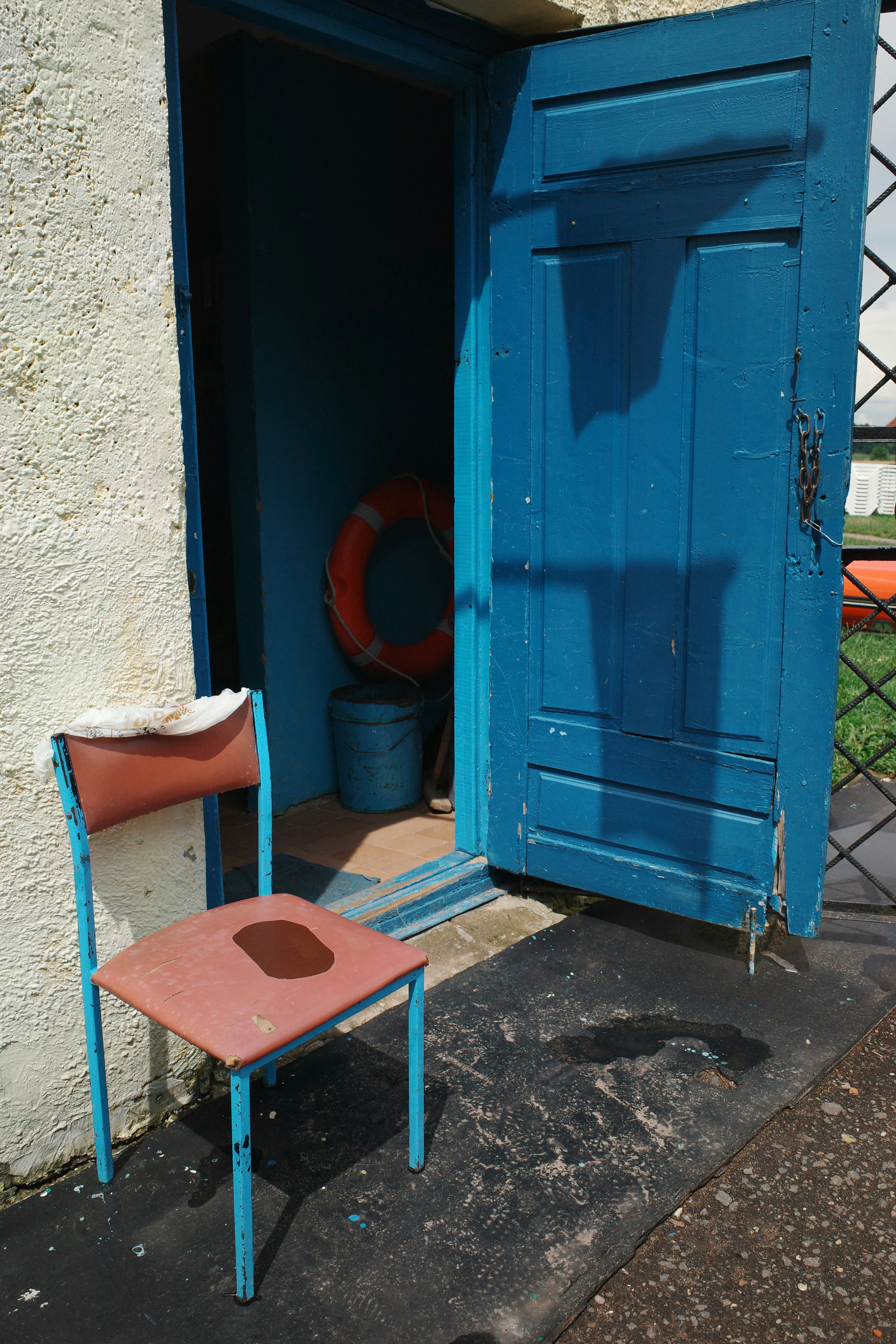 Blue Doorway with Worn Chairs: A Sunny Dockside Corner