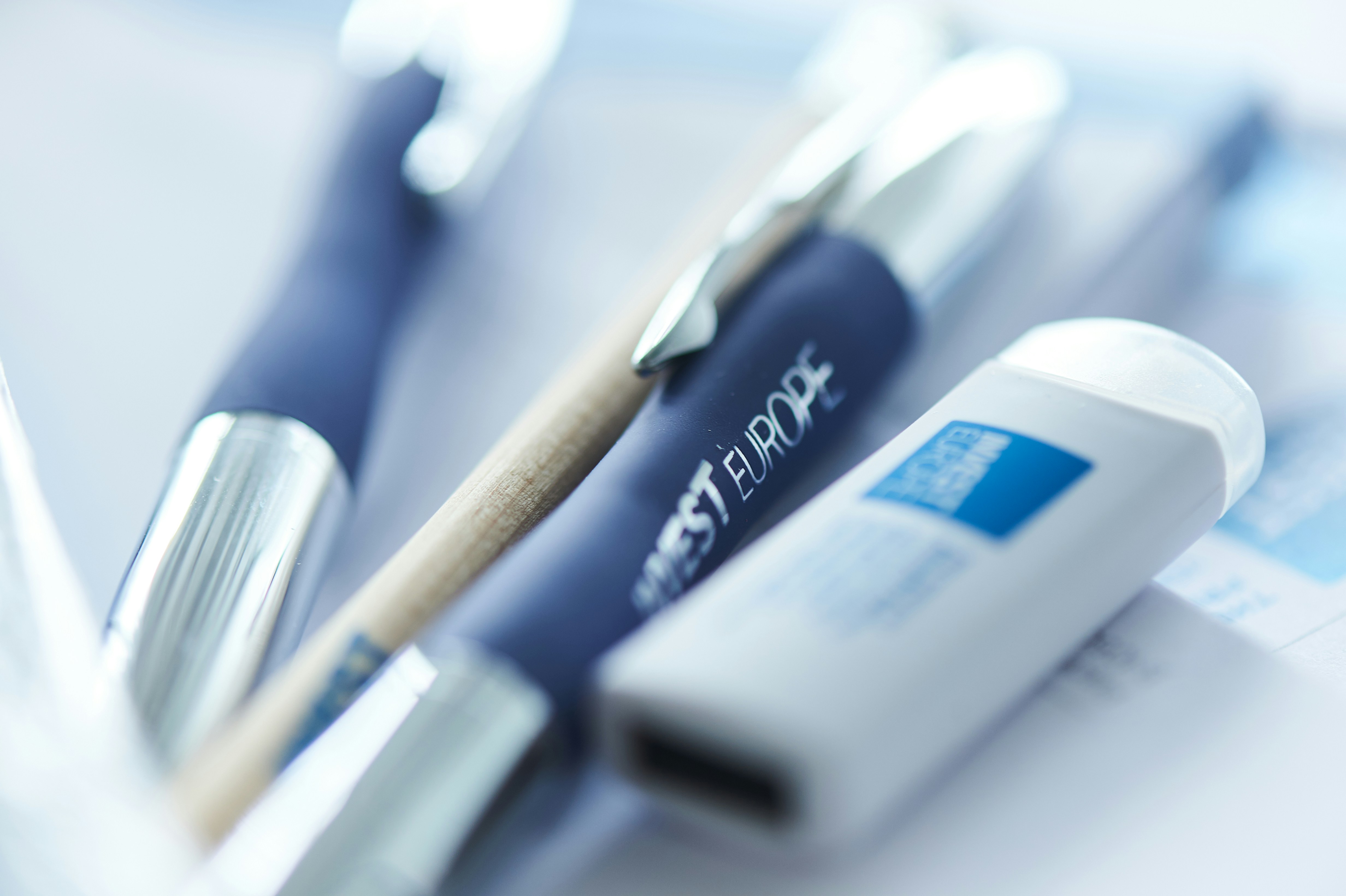 Softly blurred desk accessories with a focus on a white eraser and pens; a minimal, abstract still-life composition.