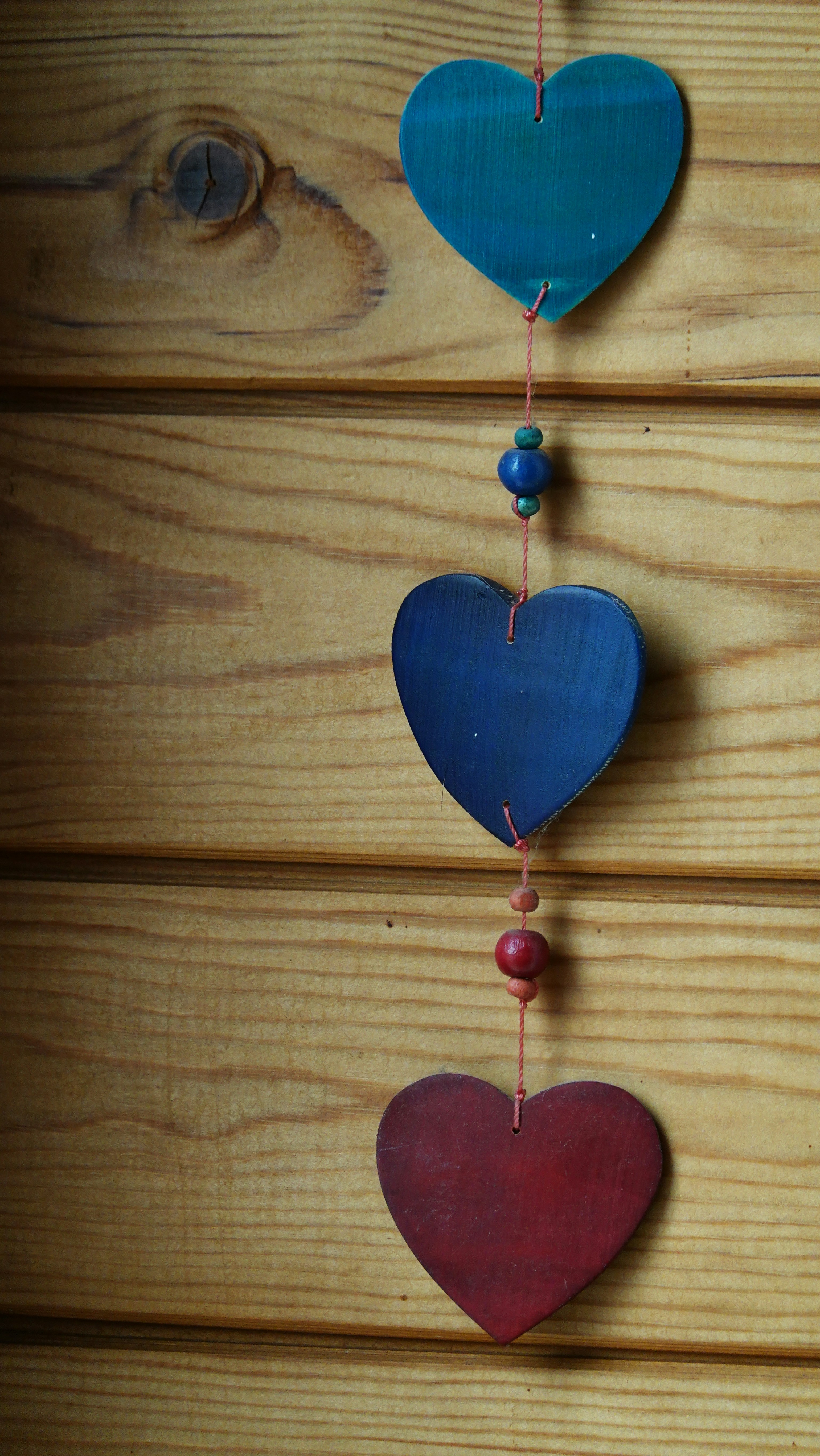 Three Matte Hearts on a Cord: a vertical string of color against warm wood