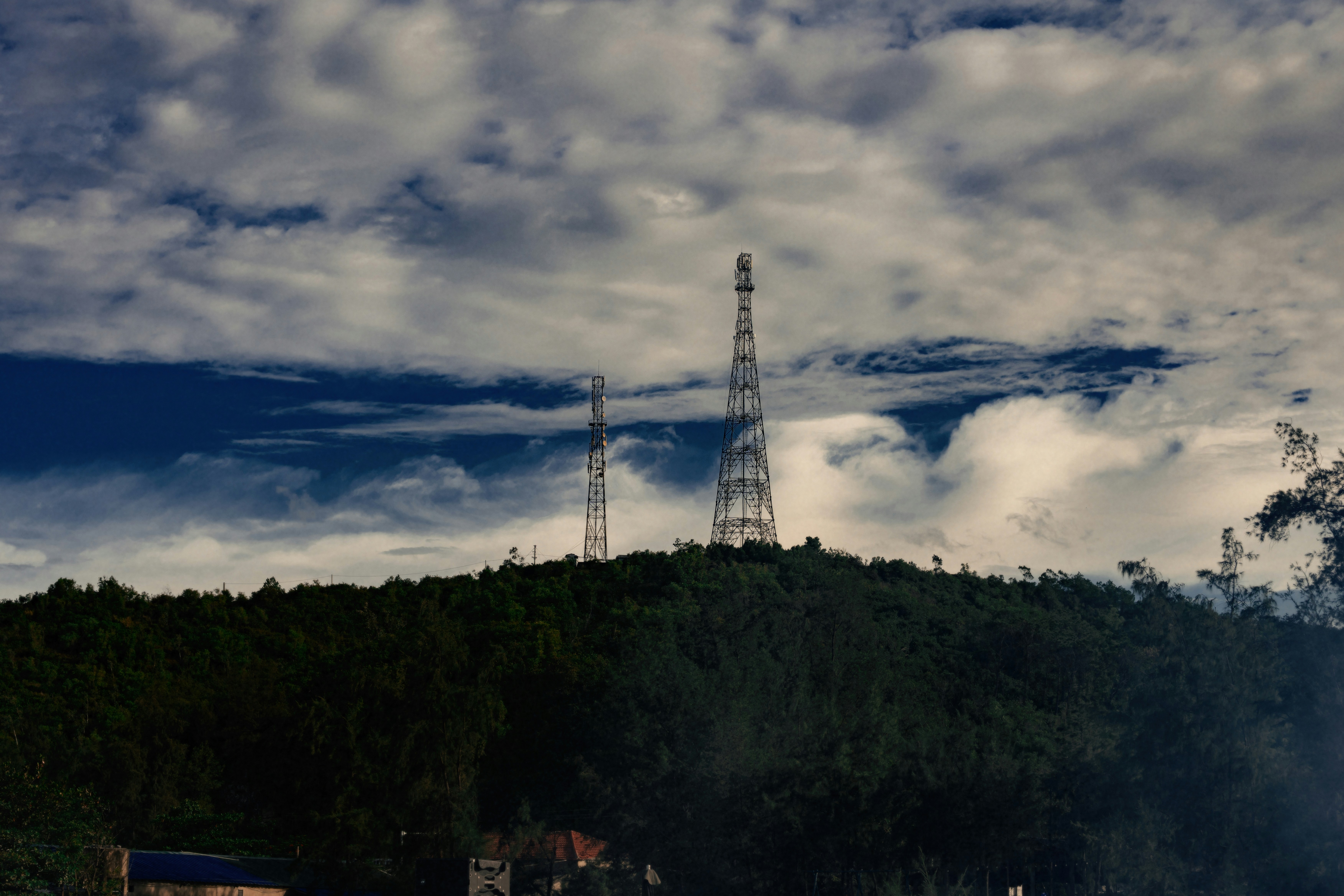 Radio Towers Reaching Above the Tree Line Under a Dramatic Sky