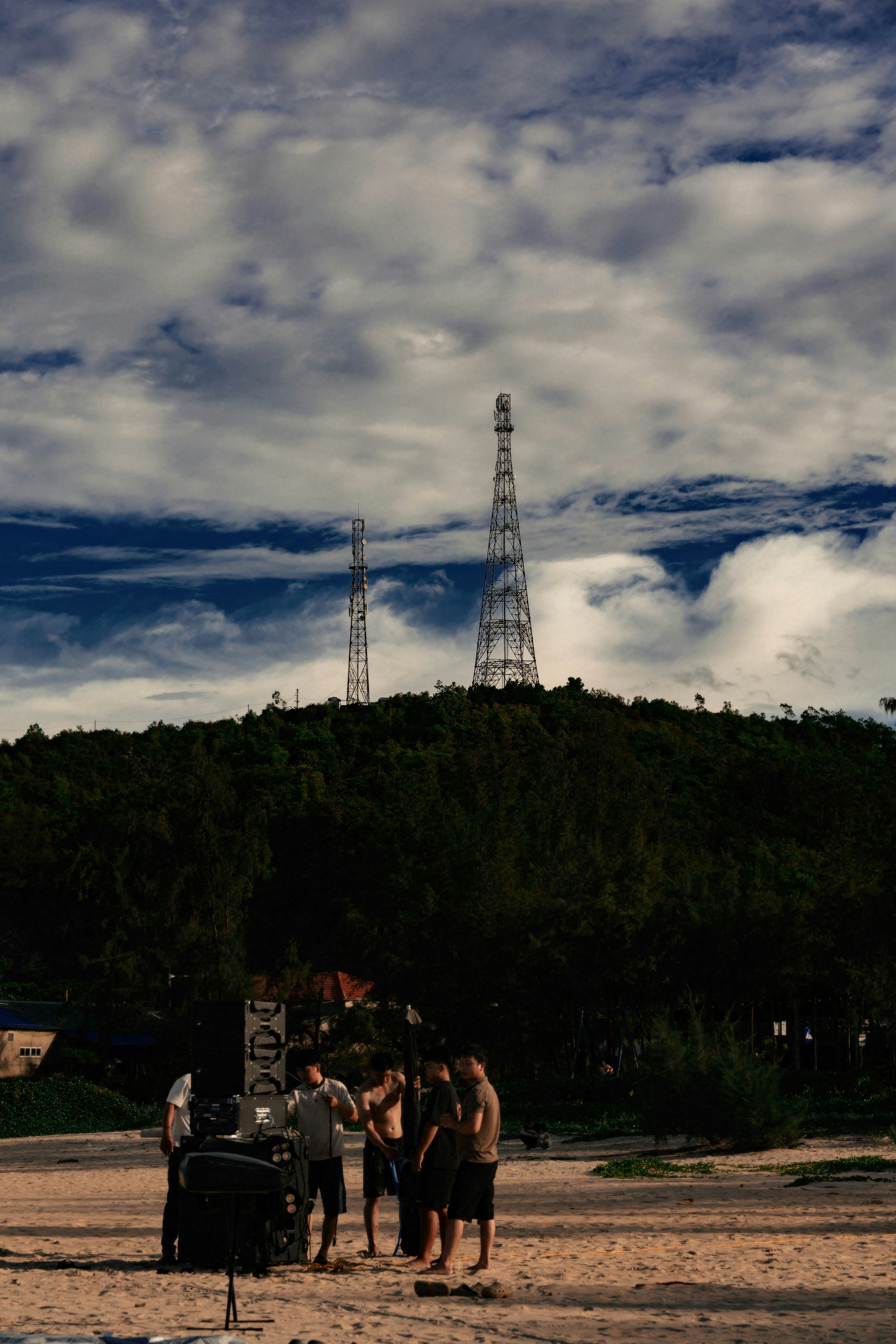 Wireless towers at dusk: a coastal crew preparing gear on the beach