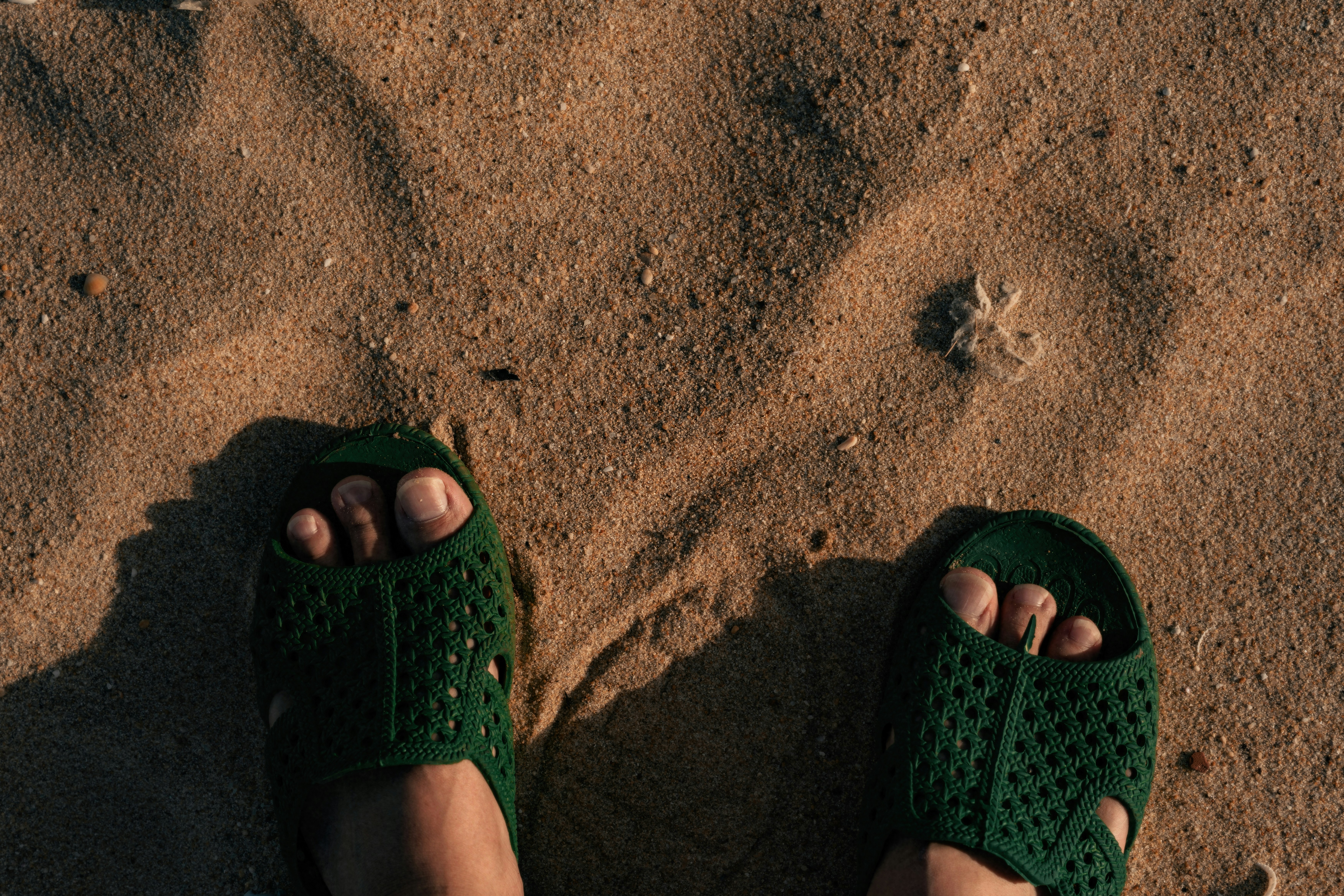 Sandbound Steps: Green Slippers on a Quiet Shore