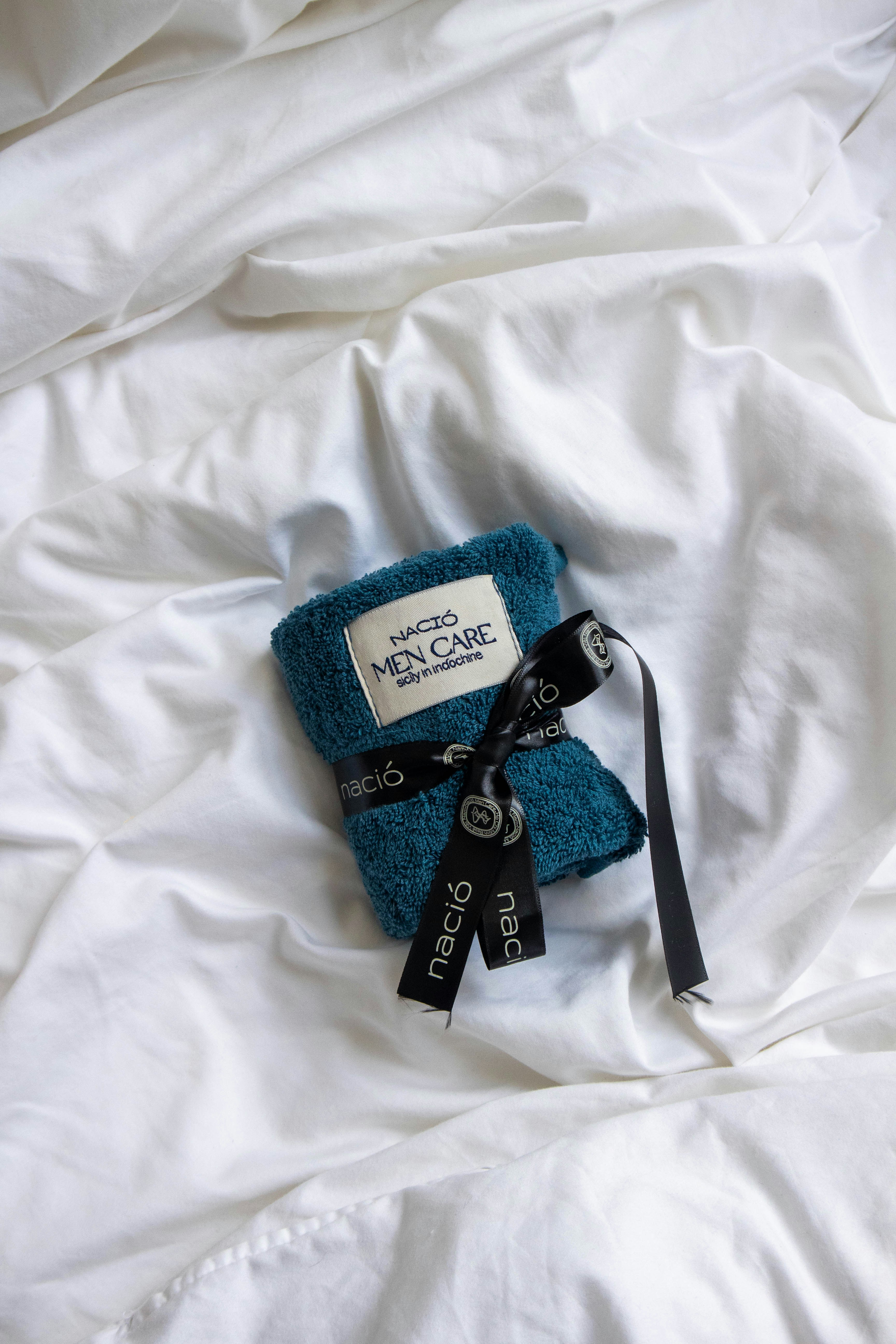 Blue towel gift set on a rumpled white bed