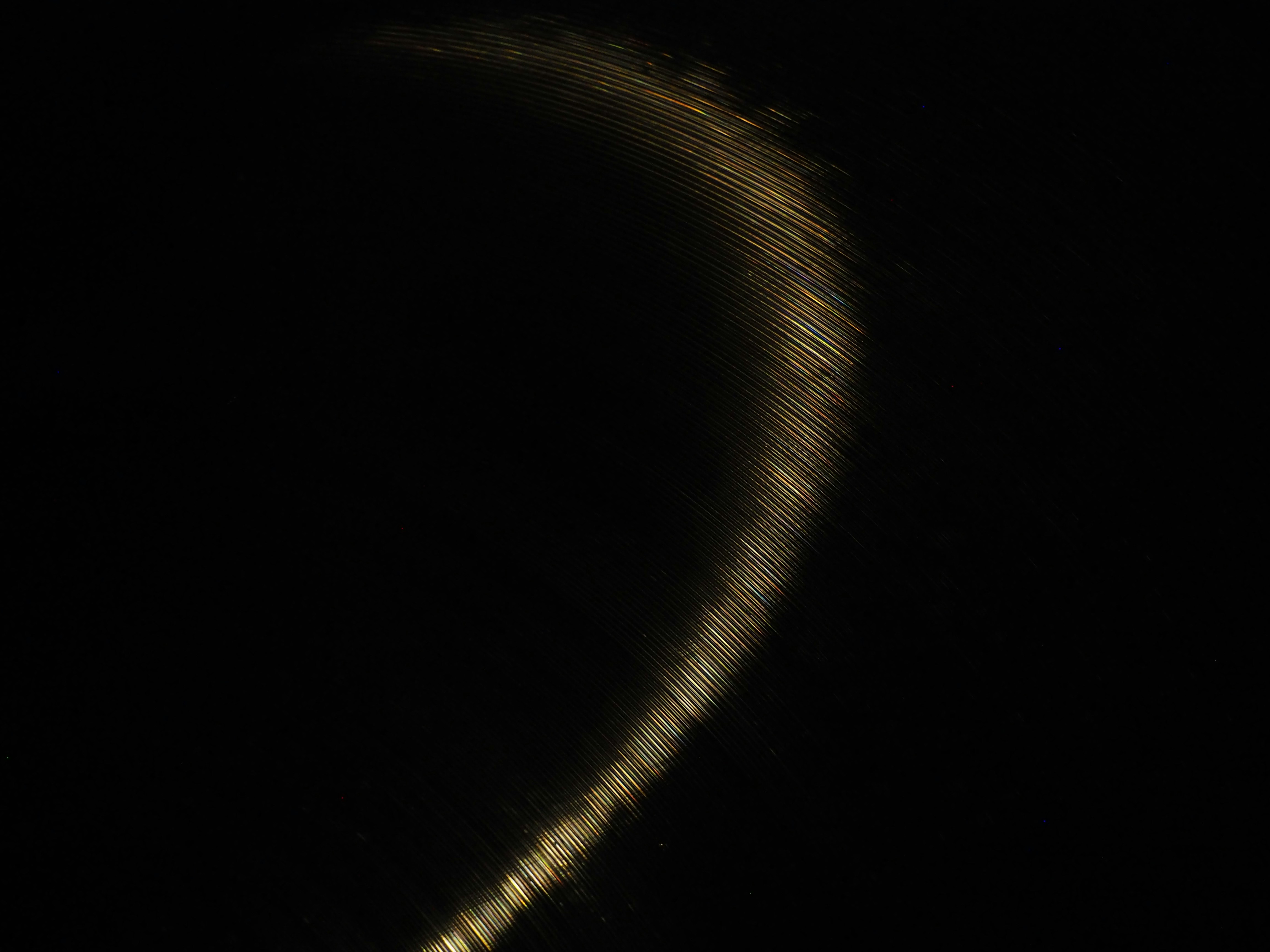 Dark abstract arc of golden light tracing a curved line against black, minimal composition. A subtle, textured stroke that suggests motion without depicting a recognisable subject.