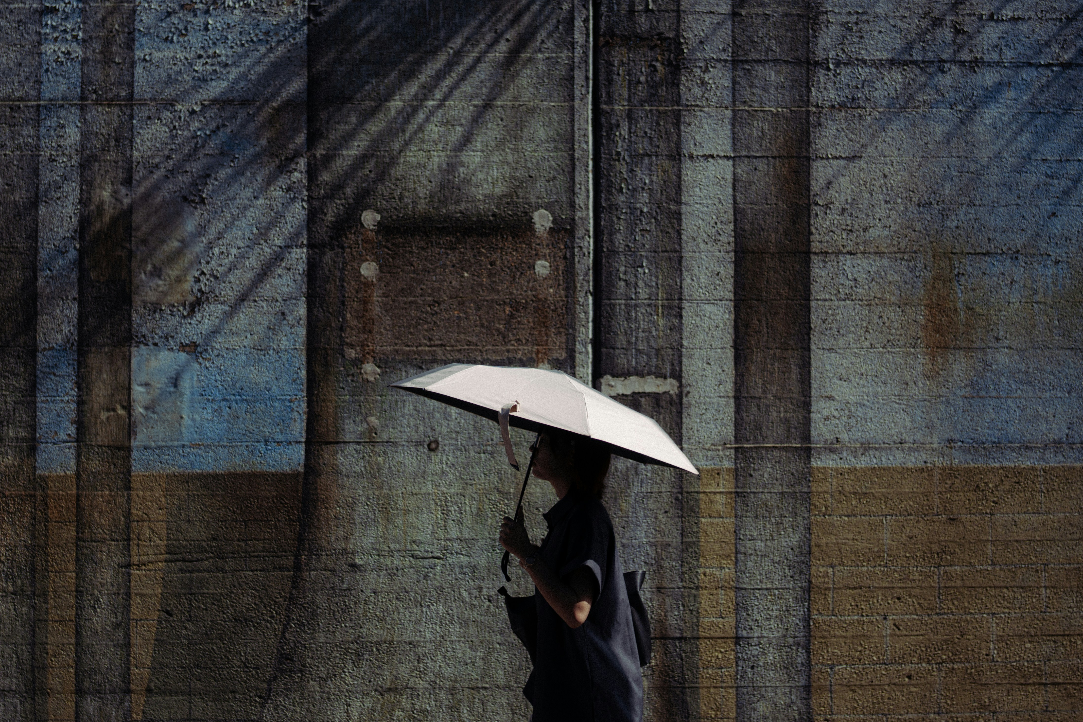 Umbrella in the Rain: A Quiet Figure Against a Textured Wall