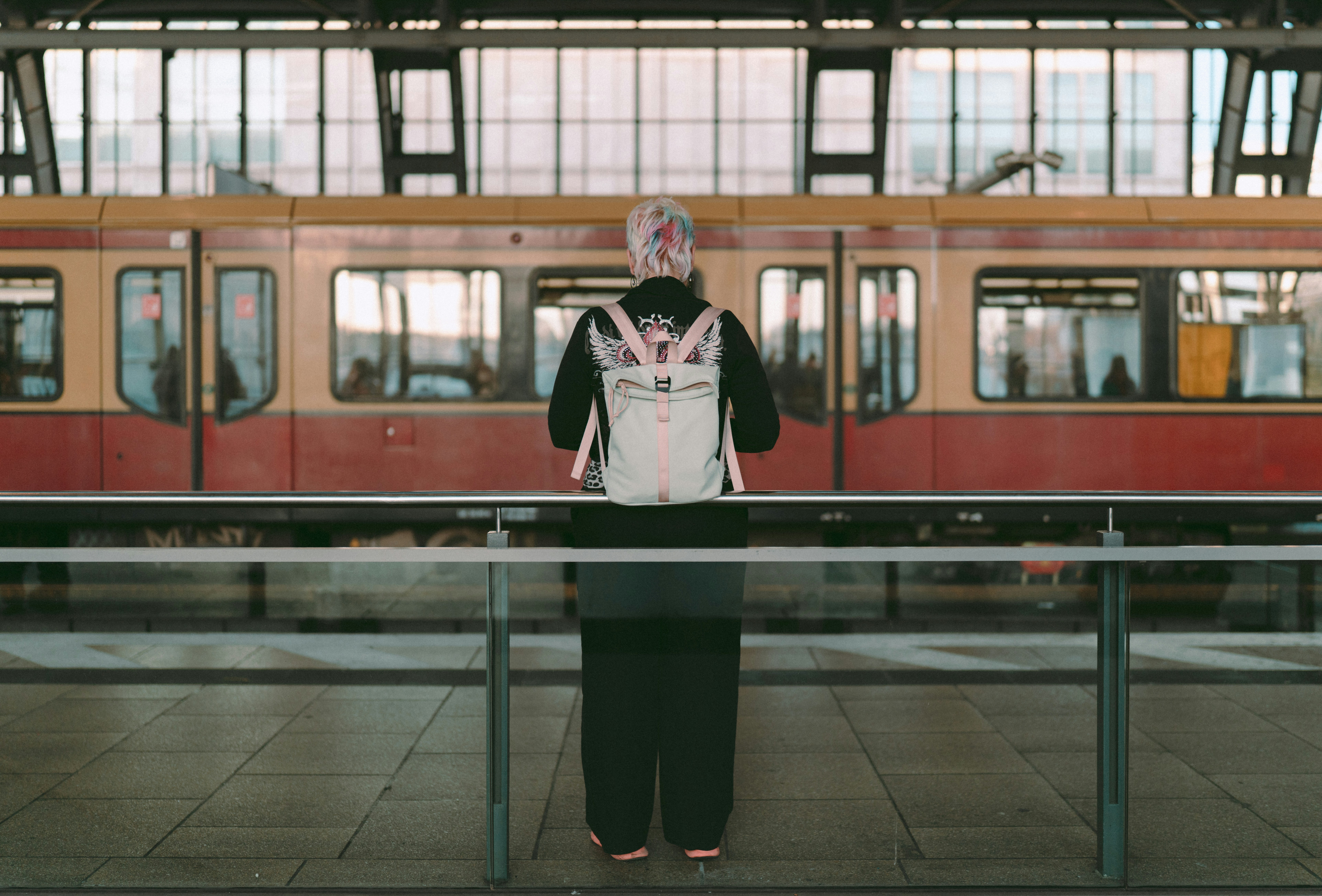 Traveler in a Quiet Station: A Backturned Moment with a Striped Train