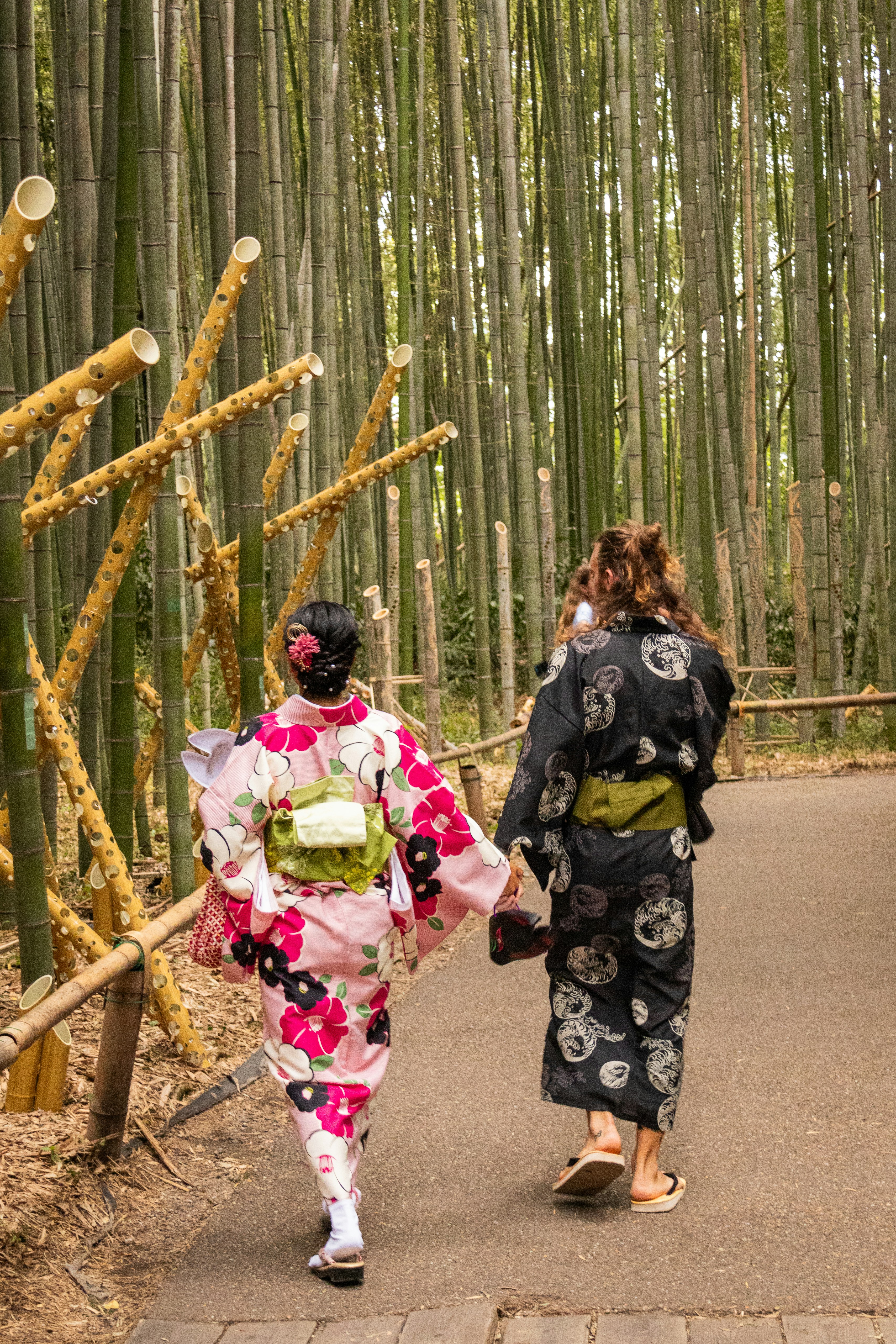 Two Women in Floral Yukata Wander Through a Bamboo Corridor
