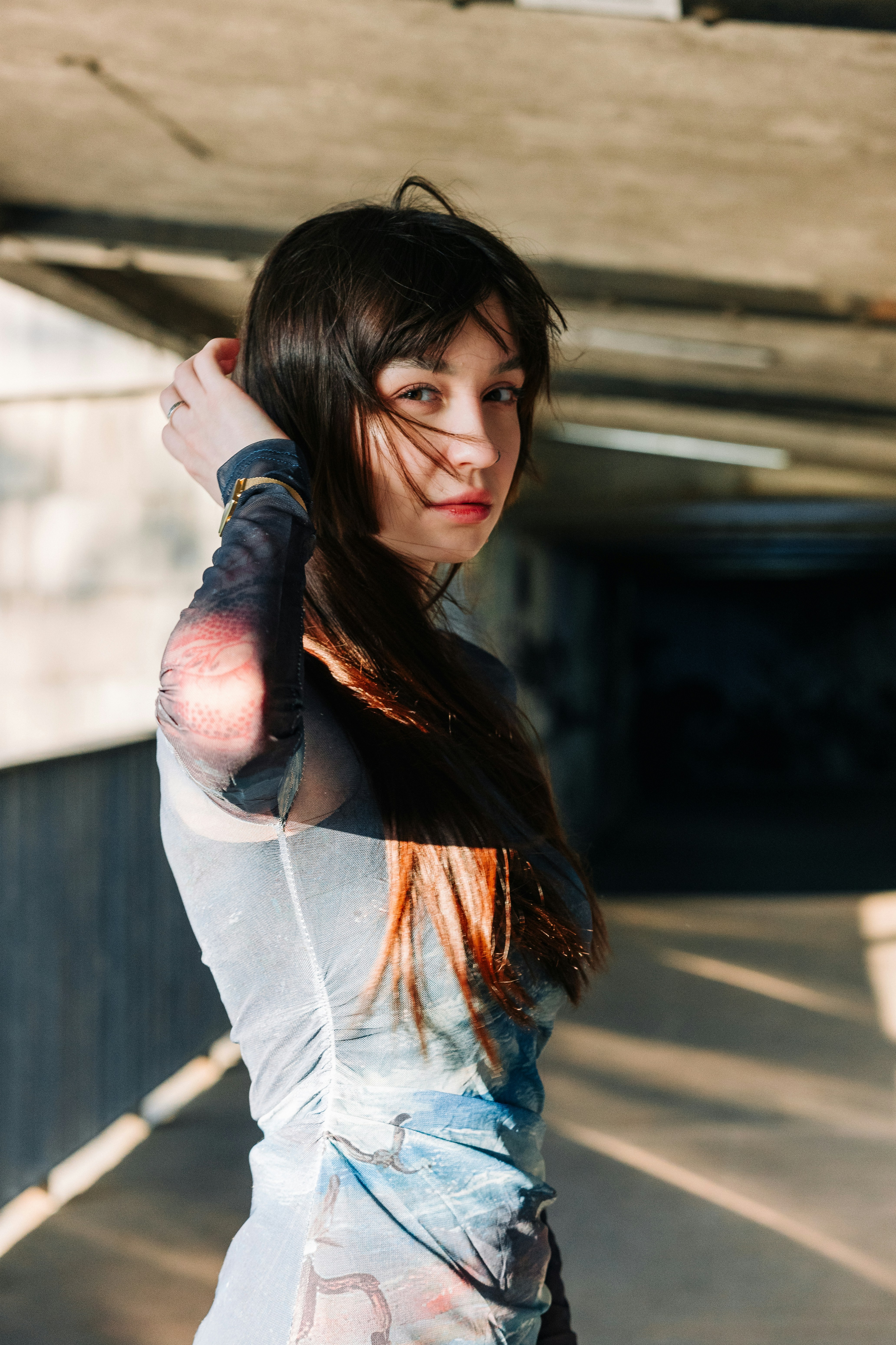 Portrait under an urban canopy: wind-tousled hair and the confident gaze