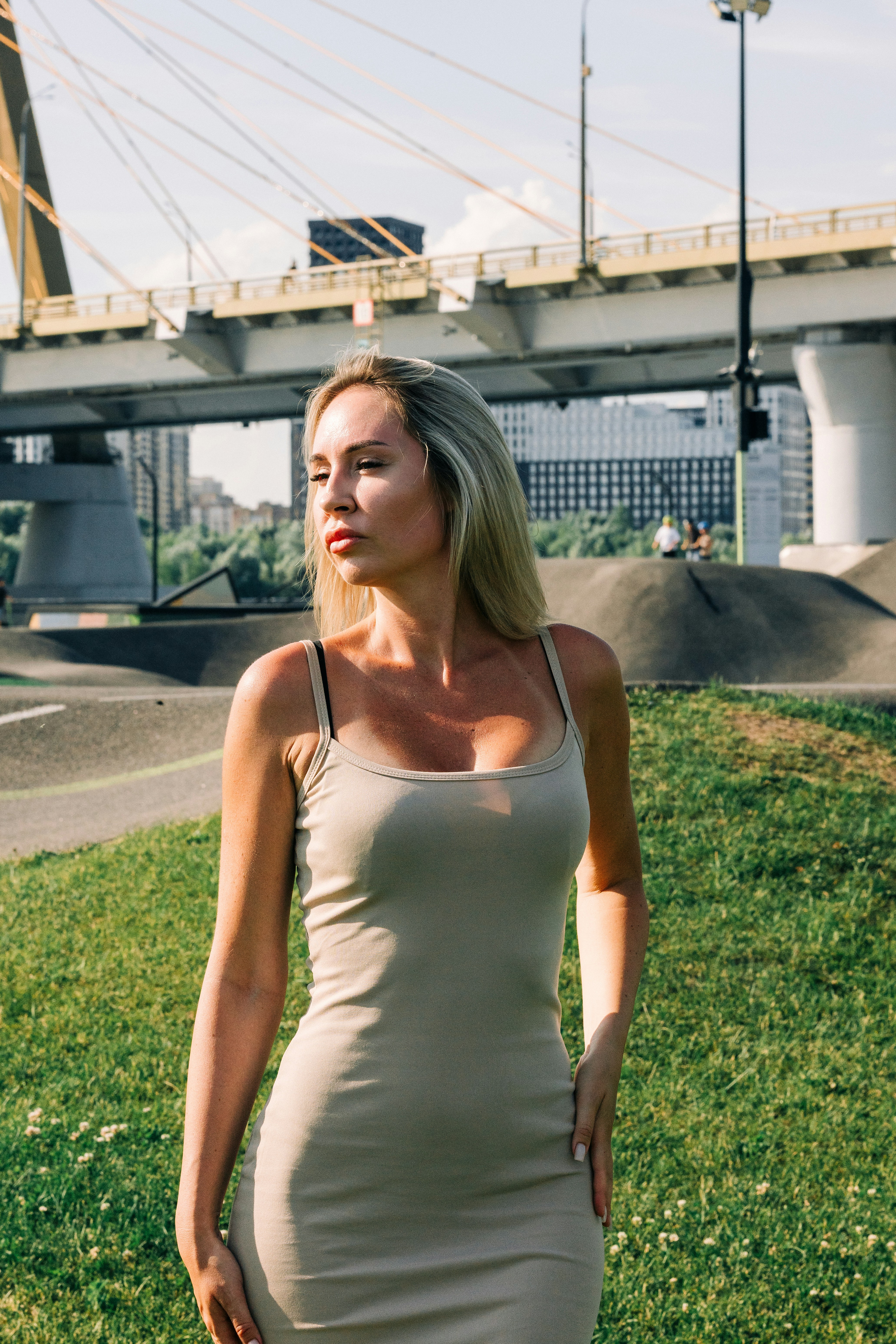 Sunlit Confidence: A Woman in a Neutral Dress Under an Urban Bridge