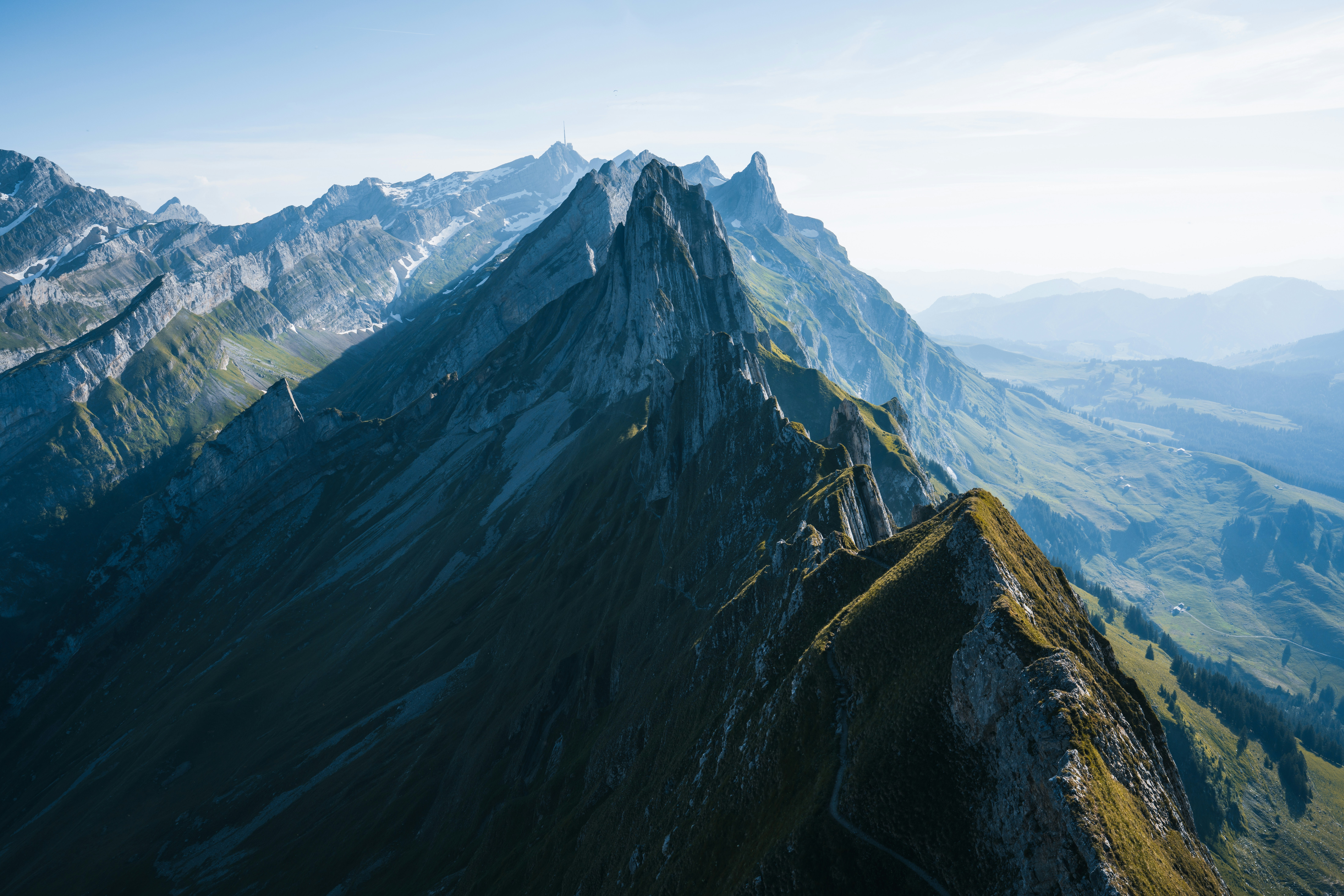 I captured this dramatic mountain ridge in the soft evening light, with the rugged peaks leading my view toward the distant Säntis massif. The steep rock faces and narrow grassy crest create a powerful sense of depth, while the warm sunlight touches the ridge and contrasts beautifully with the cool blue shadows. In the distance, the landscape gradually fades into atmospheric haze, giving the scene a calm and almost endless feeling. I especially like how the ridge acts as a natural leading line through this impressive alpine landscape.