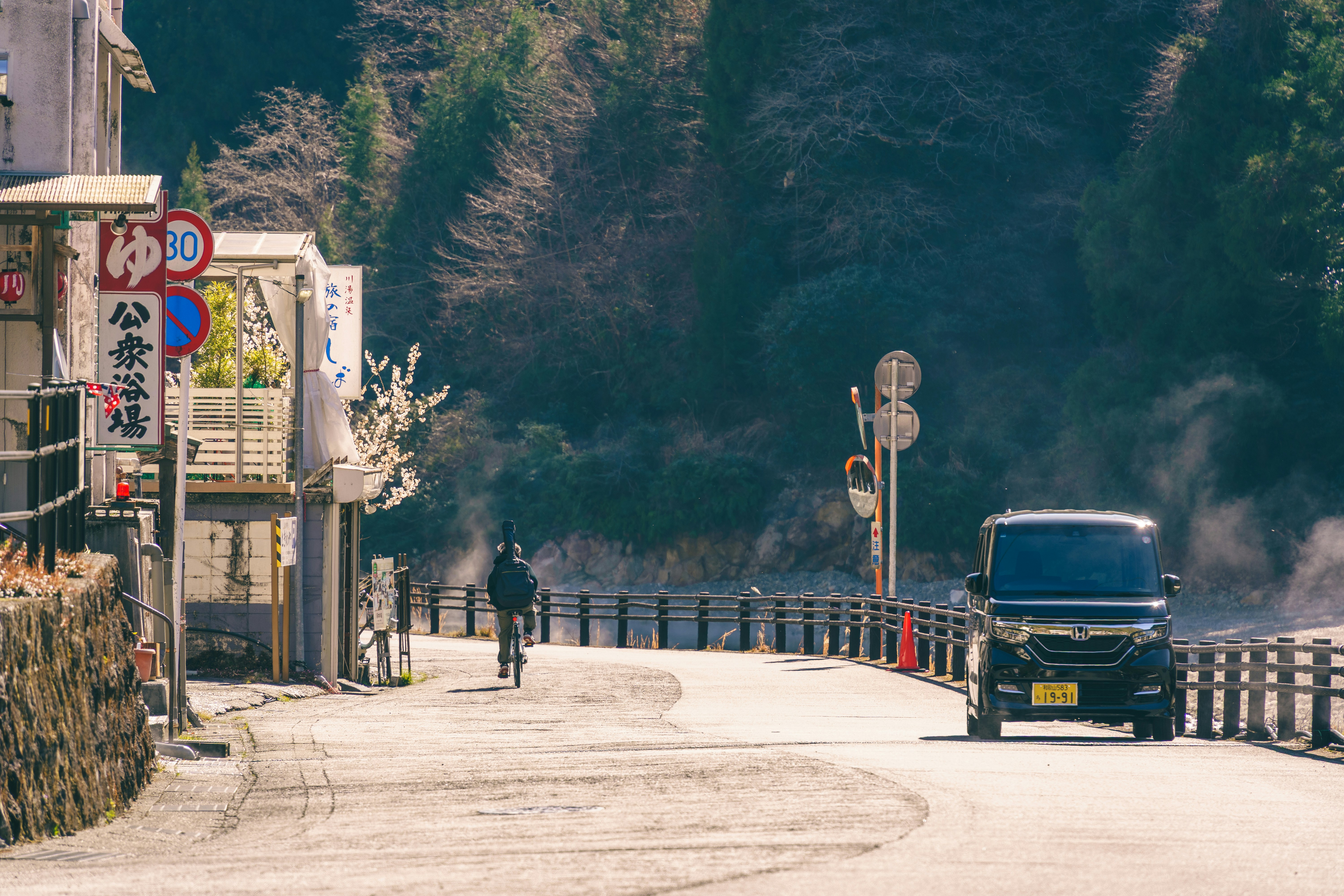 Quiet Riverside Road: Cyclist Ahead with a Distant Lake View