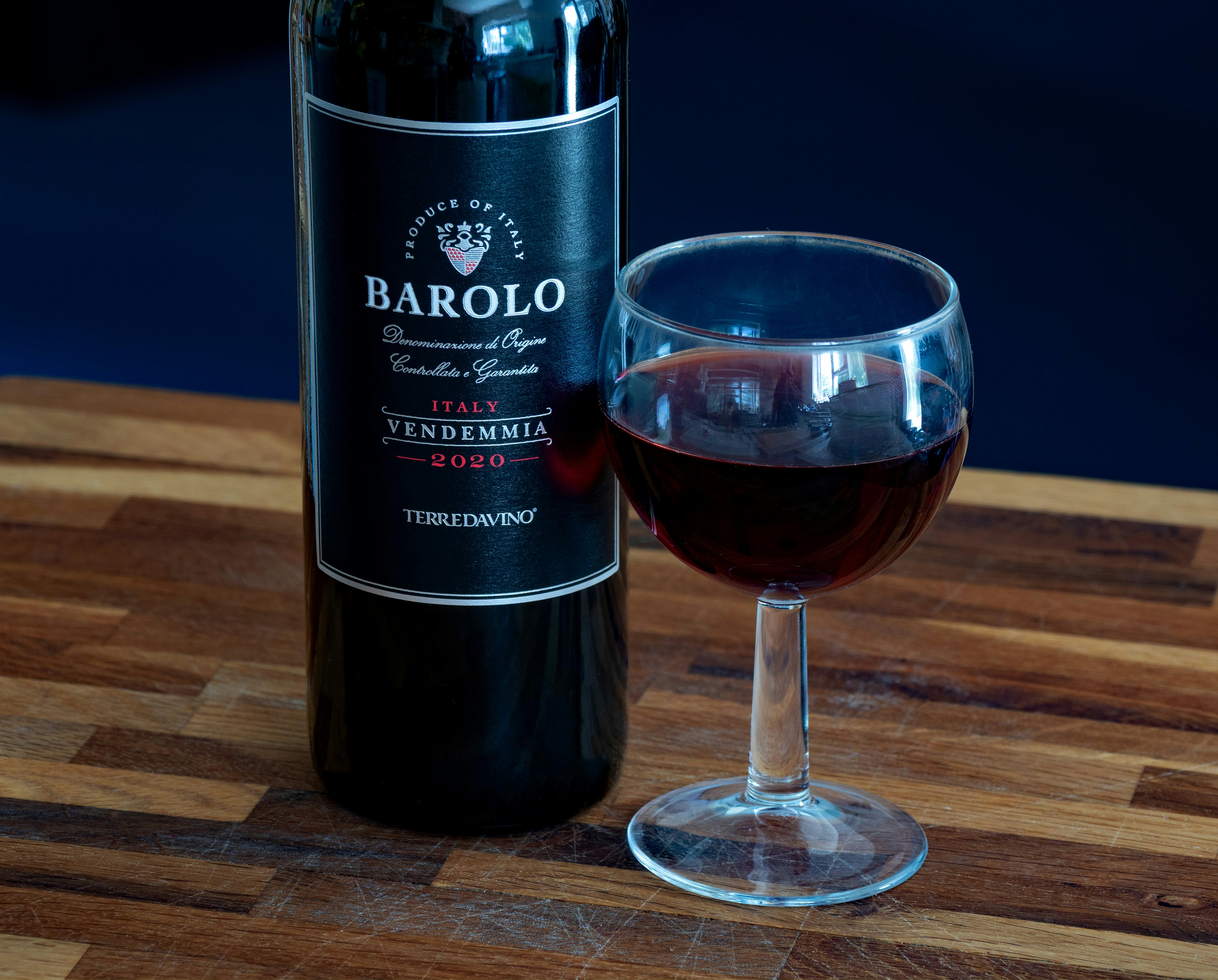 Barolo on a Wooden Stage: A Glass of Red with the Bottle's Portrait