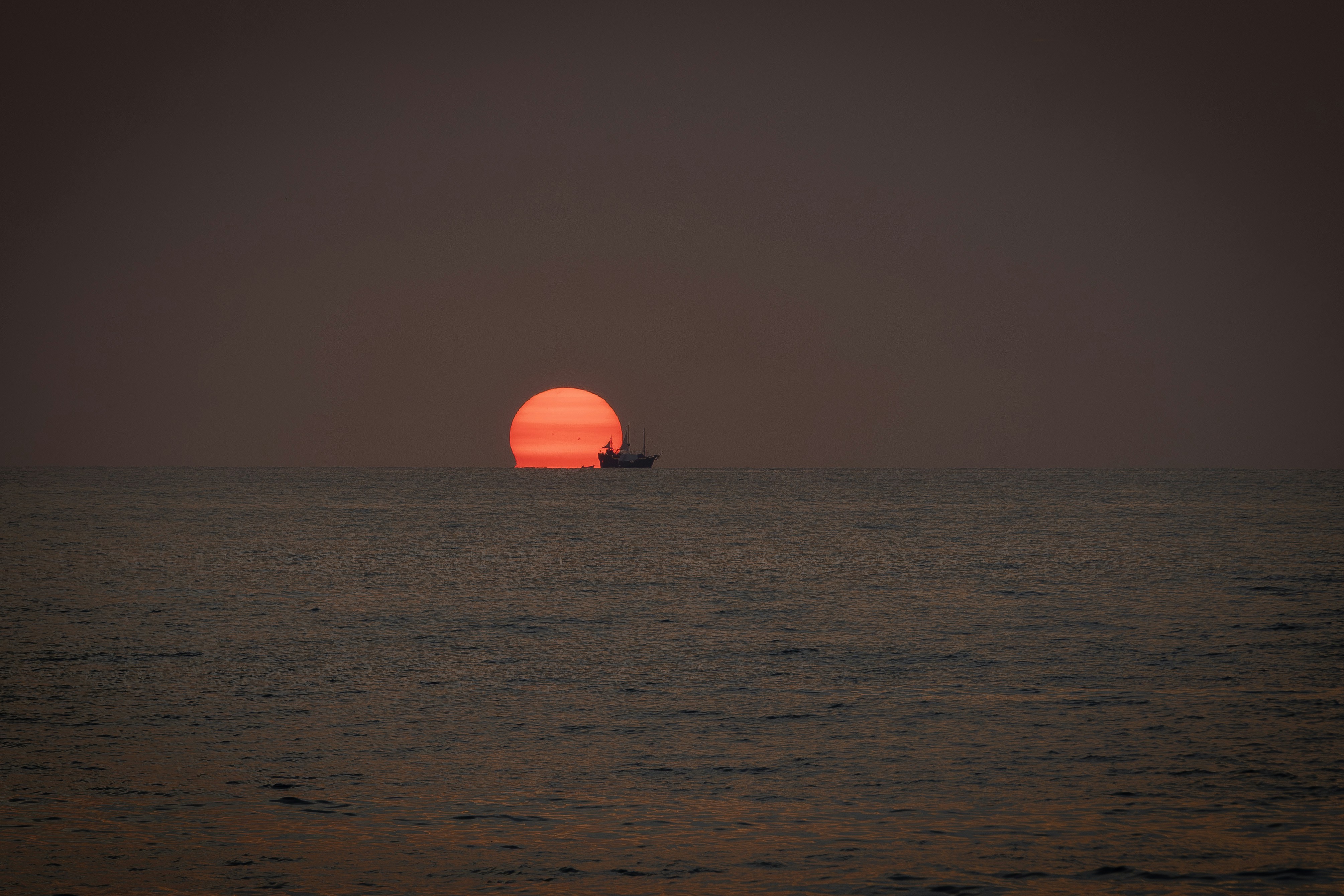 Red Sun on the Horizon: A Quiet Boat at Dusk