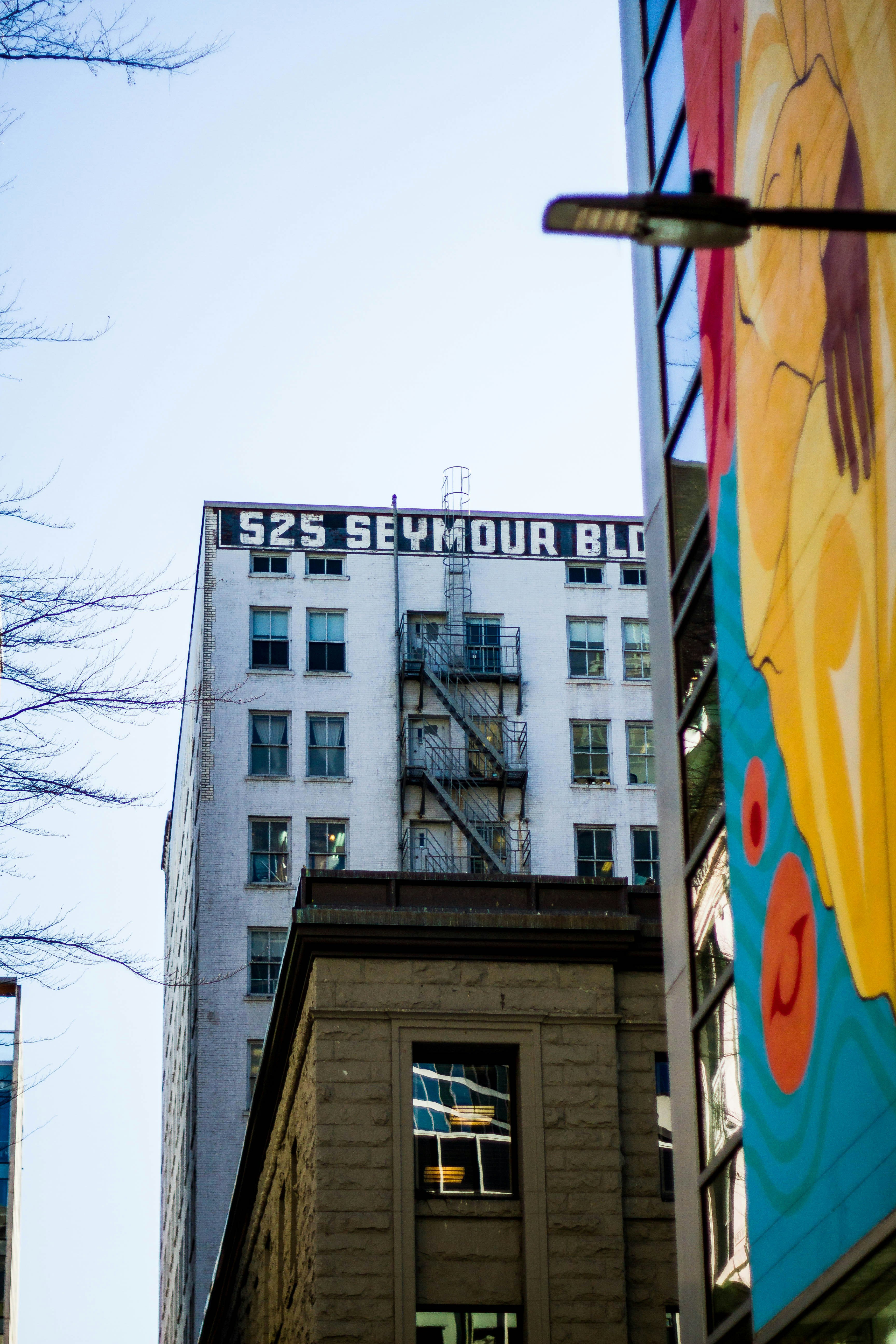 Urban mural and fire escape: a city’s vertical rhythm beneath a weathered sign