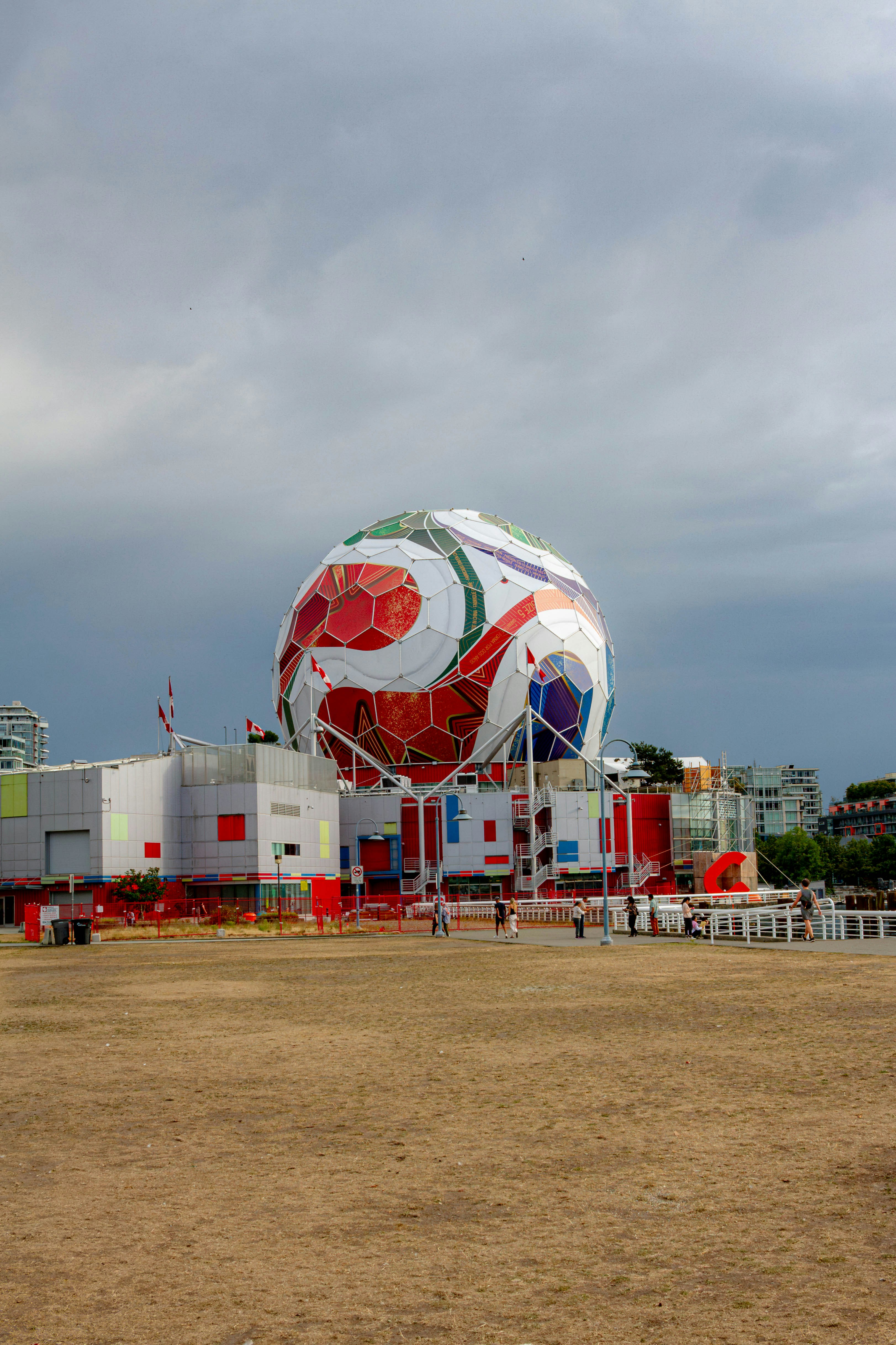 Geometric sphere at the harbor: mosaic playground under a stormy sky