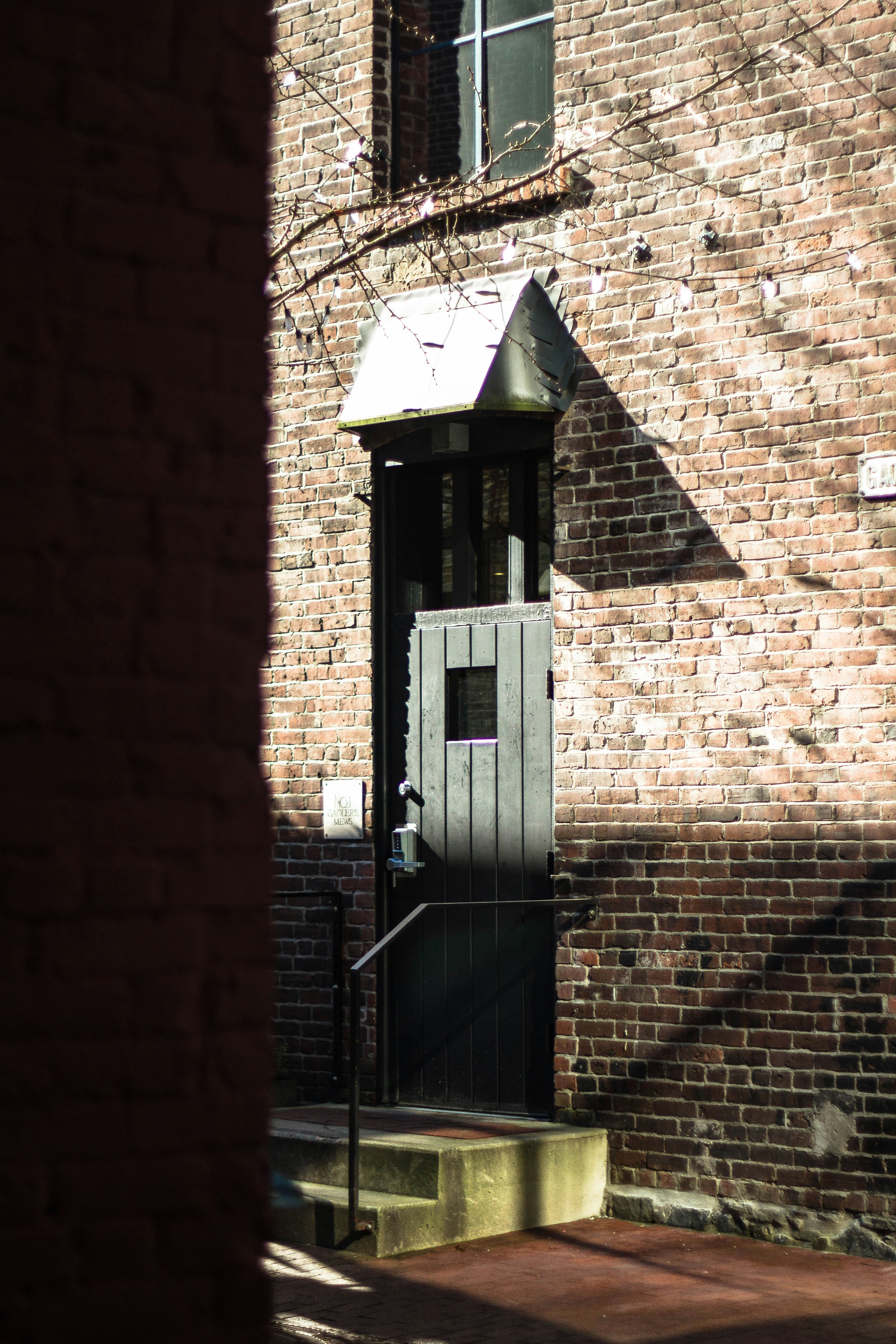 Brick doorway in shadow: sunlight catches a lone stairwell door