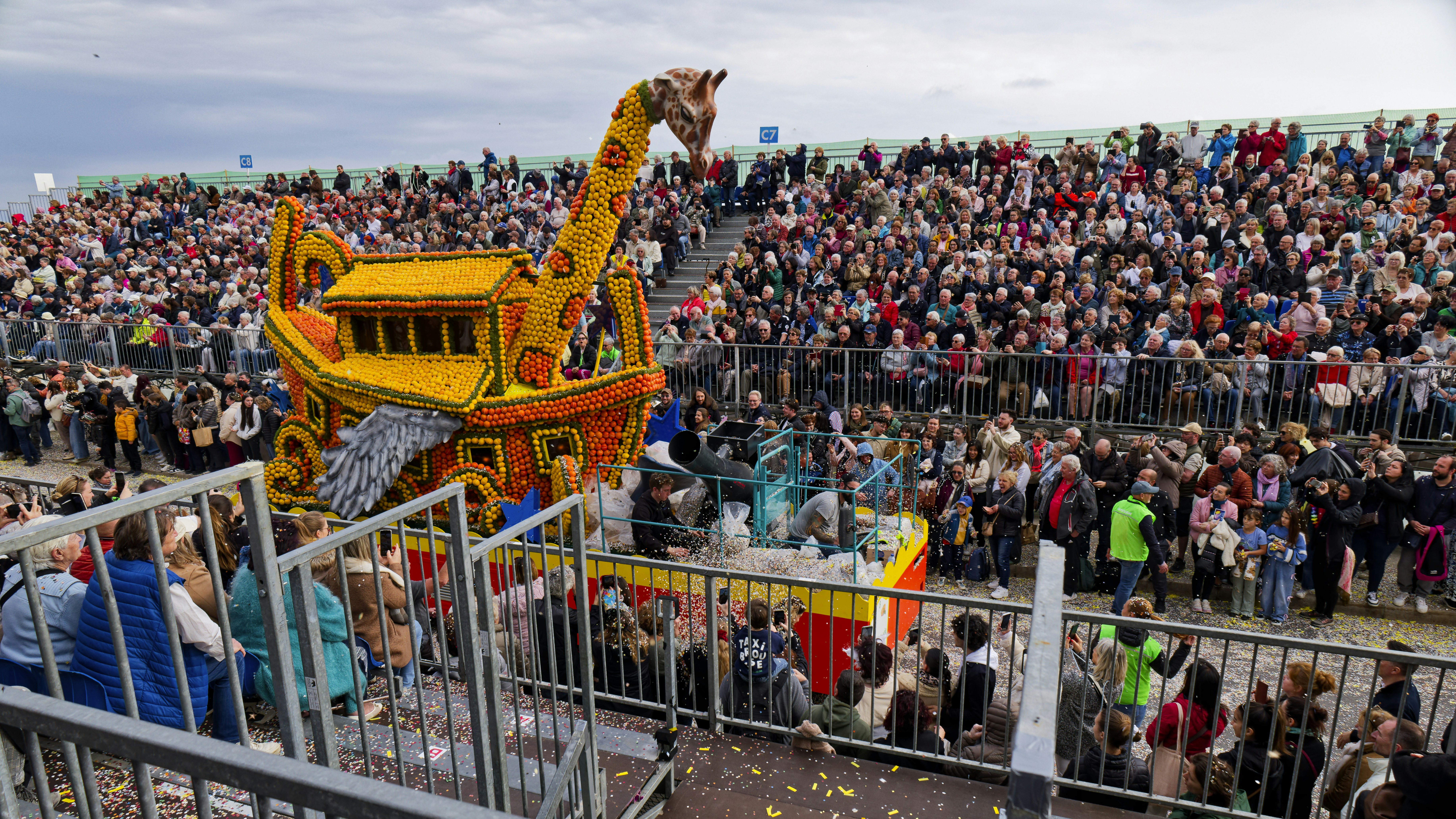 Colorful float procession erupts through a packed seaside crowd
