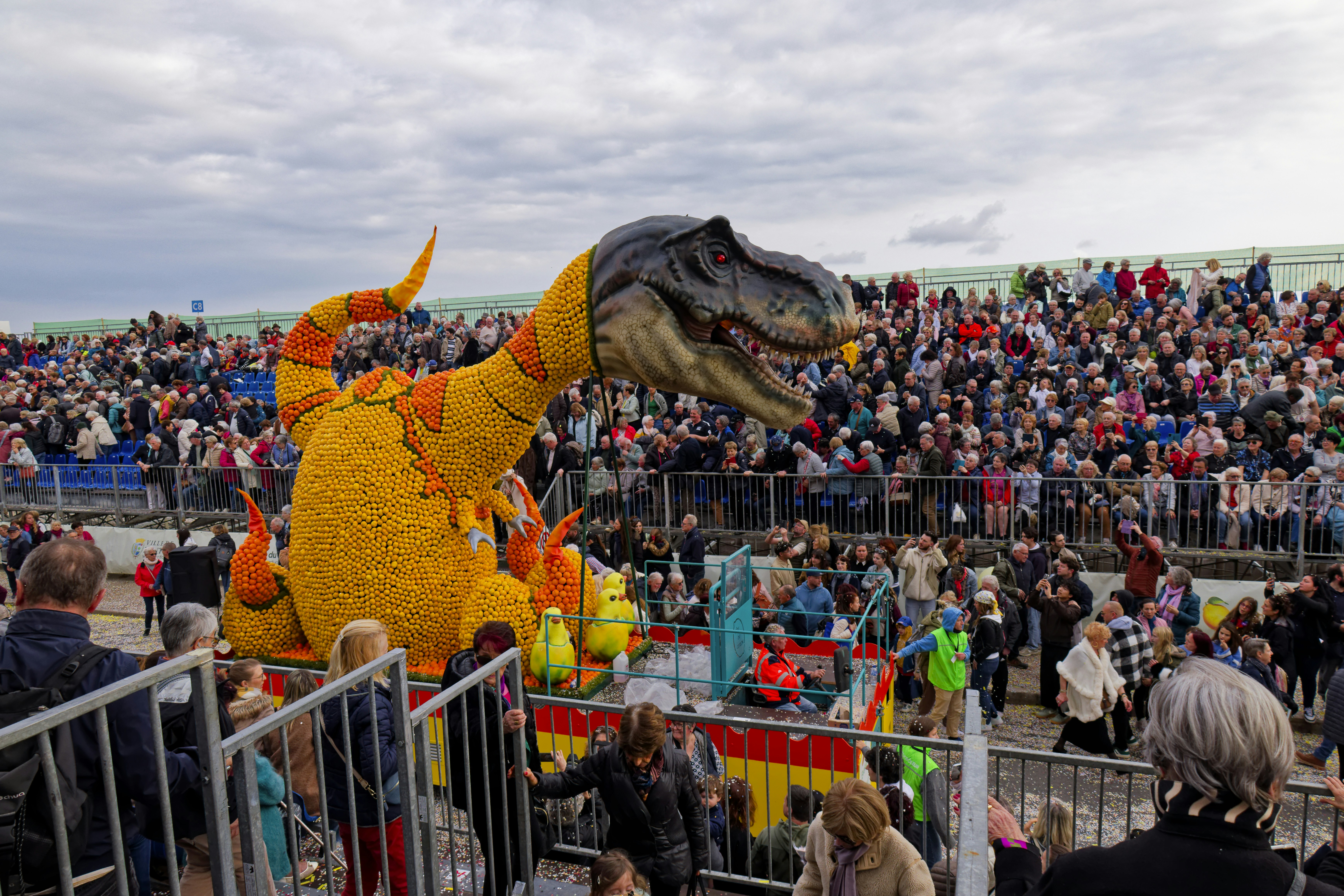 Giant Dino on Parade: A Colorful Ceratosaur Stands Over a Sea of Spectators