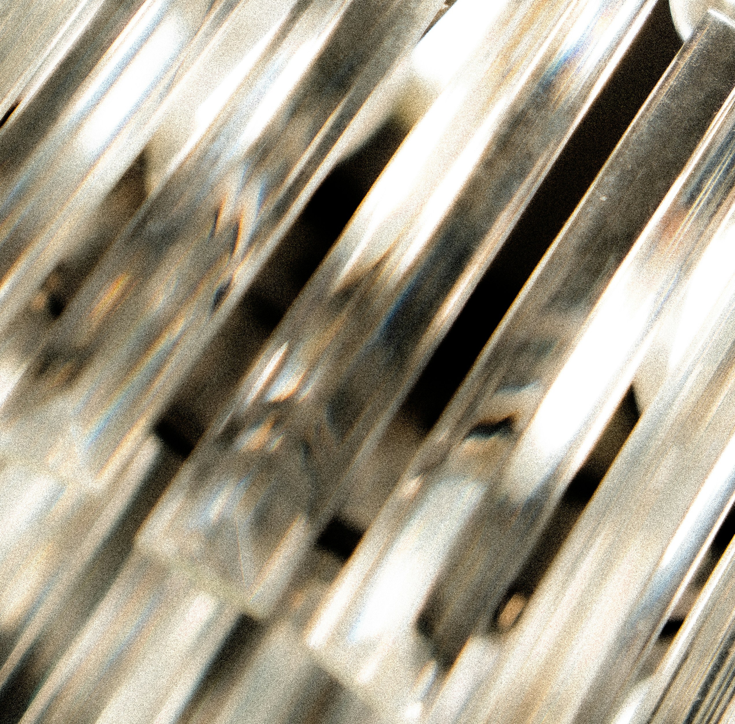 Abstract close-up of metallic strips in motion, creating dynamic reflections and depth. This is a photographic study focusing on texture and light rather than a identifiable subject.