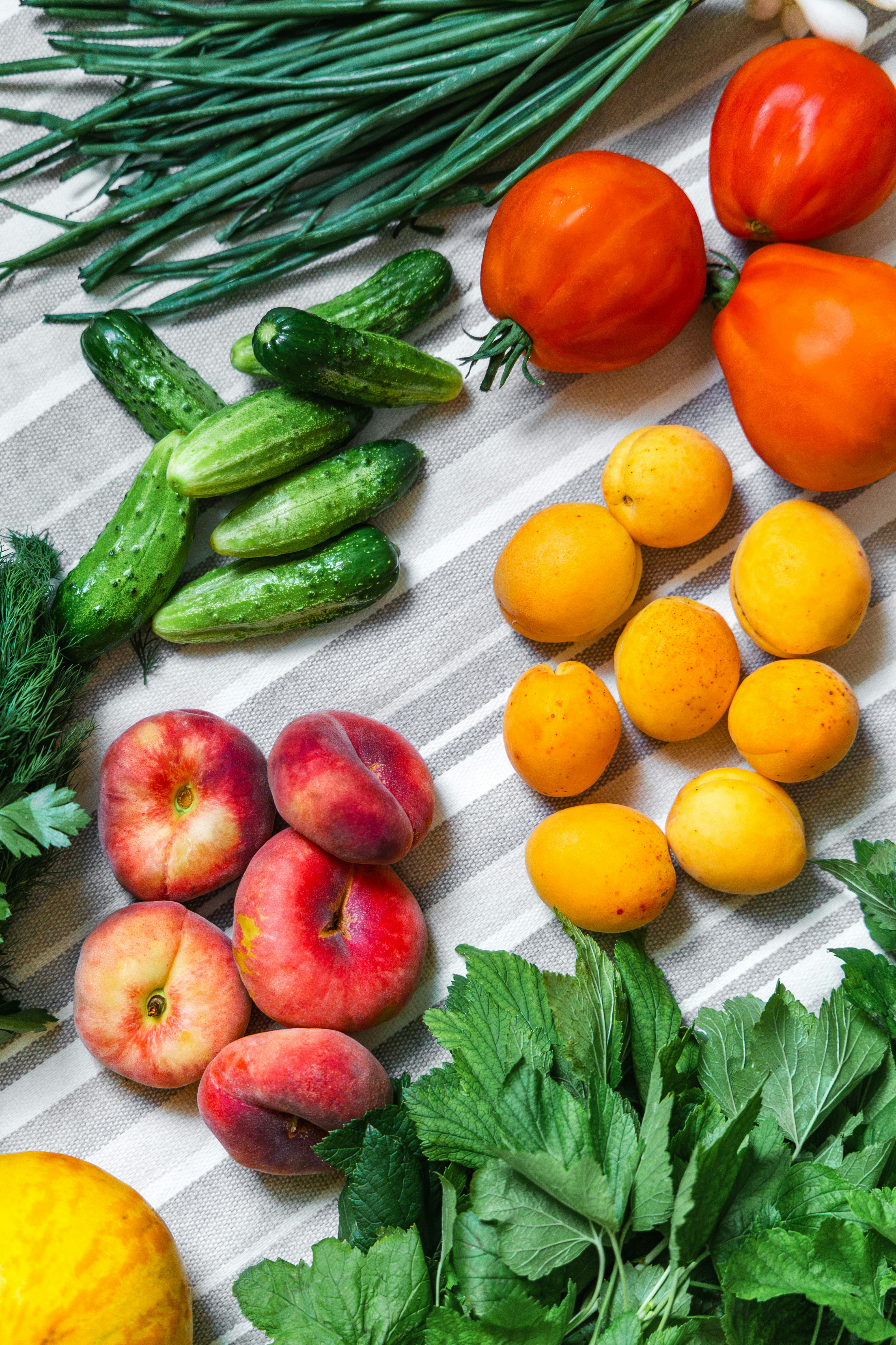 Harvest Mosaic: A diagonal display of cucumbers, peaches, and lemons on striped cloth