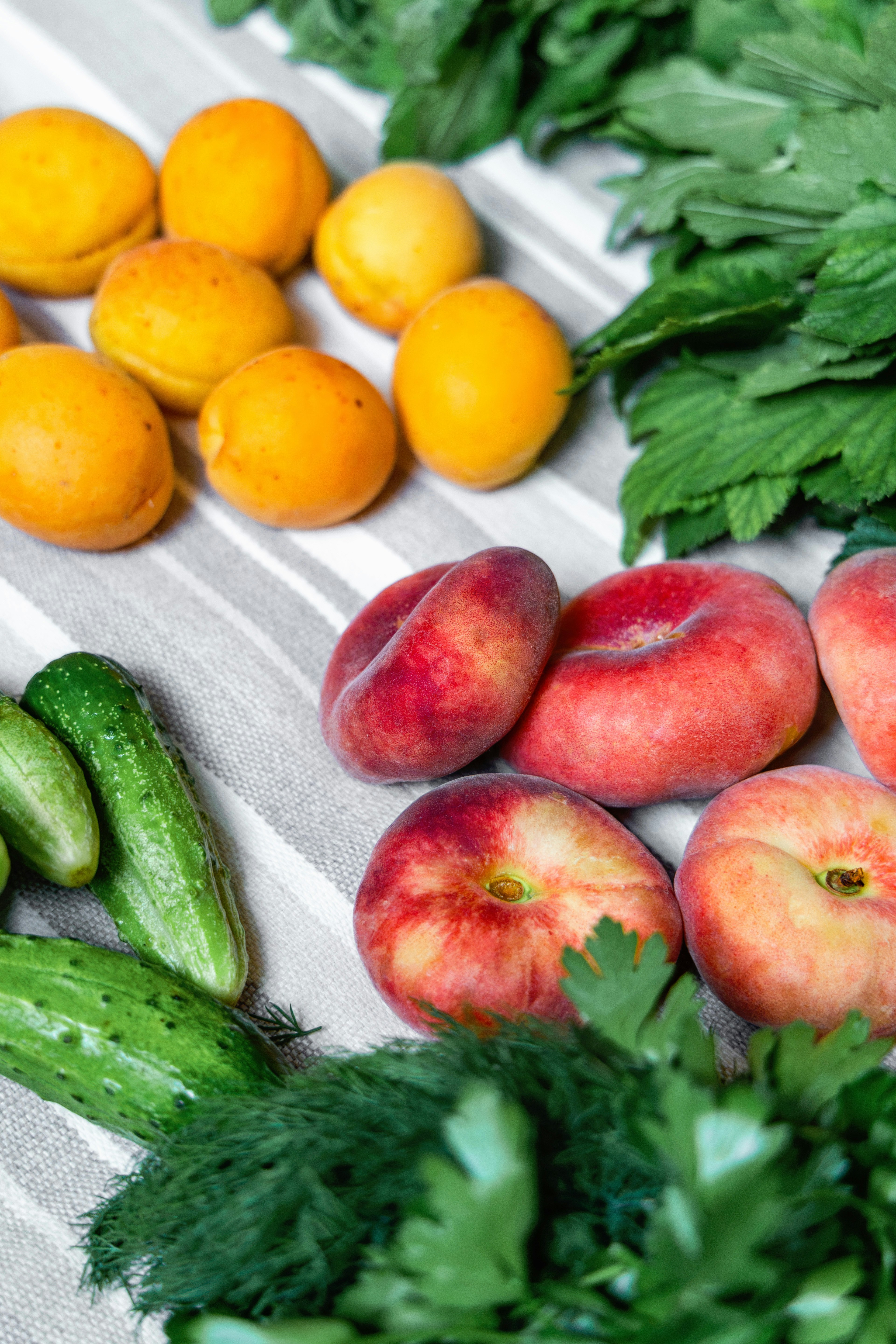 Sunlit Orchard Still Life: Apricots, Peaches, and Greens on Striped Linen
