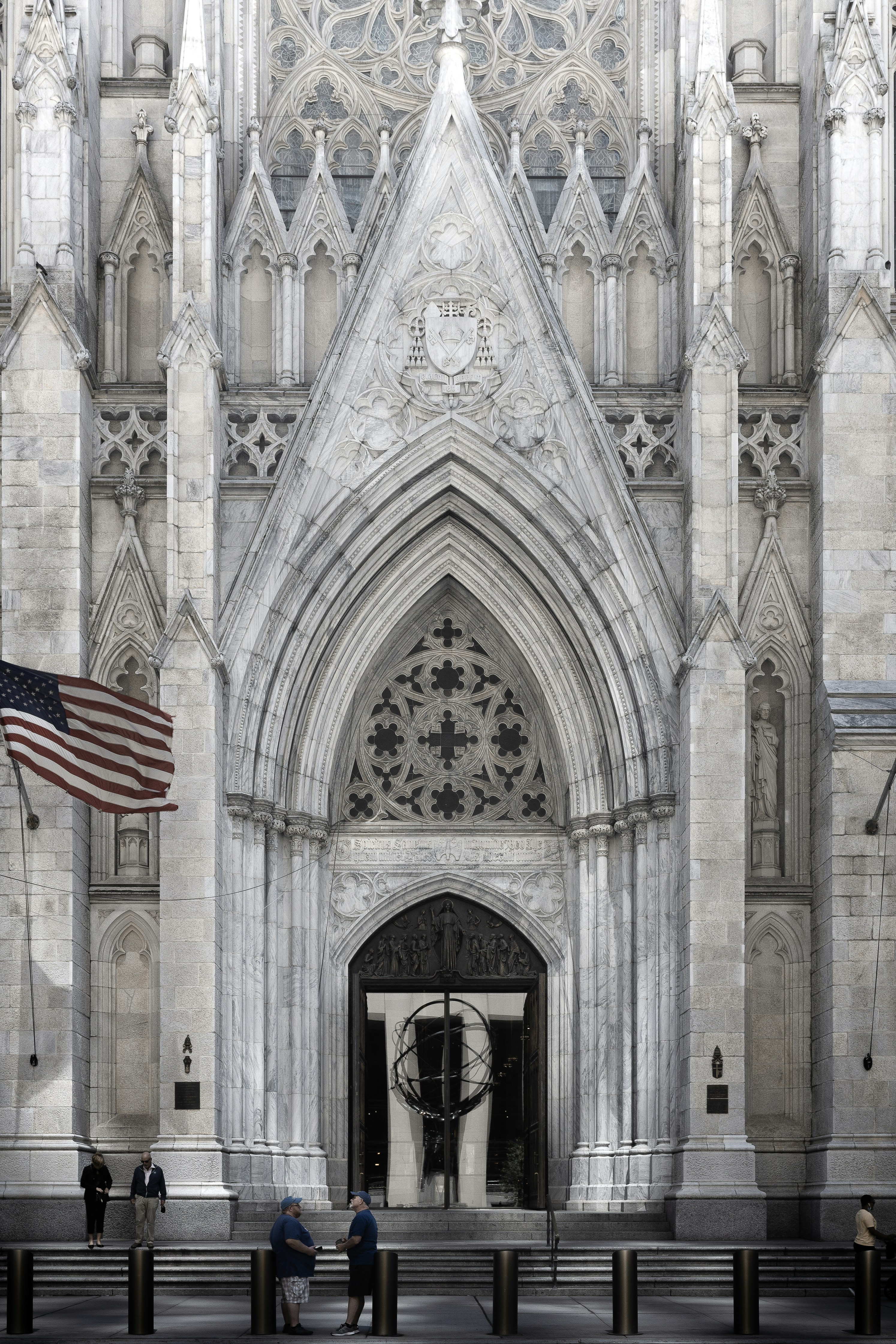 Gothic Portal at Dusk: Stone Cathedral with Flag and Silhouetted Visitors