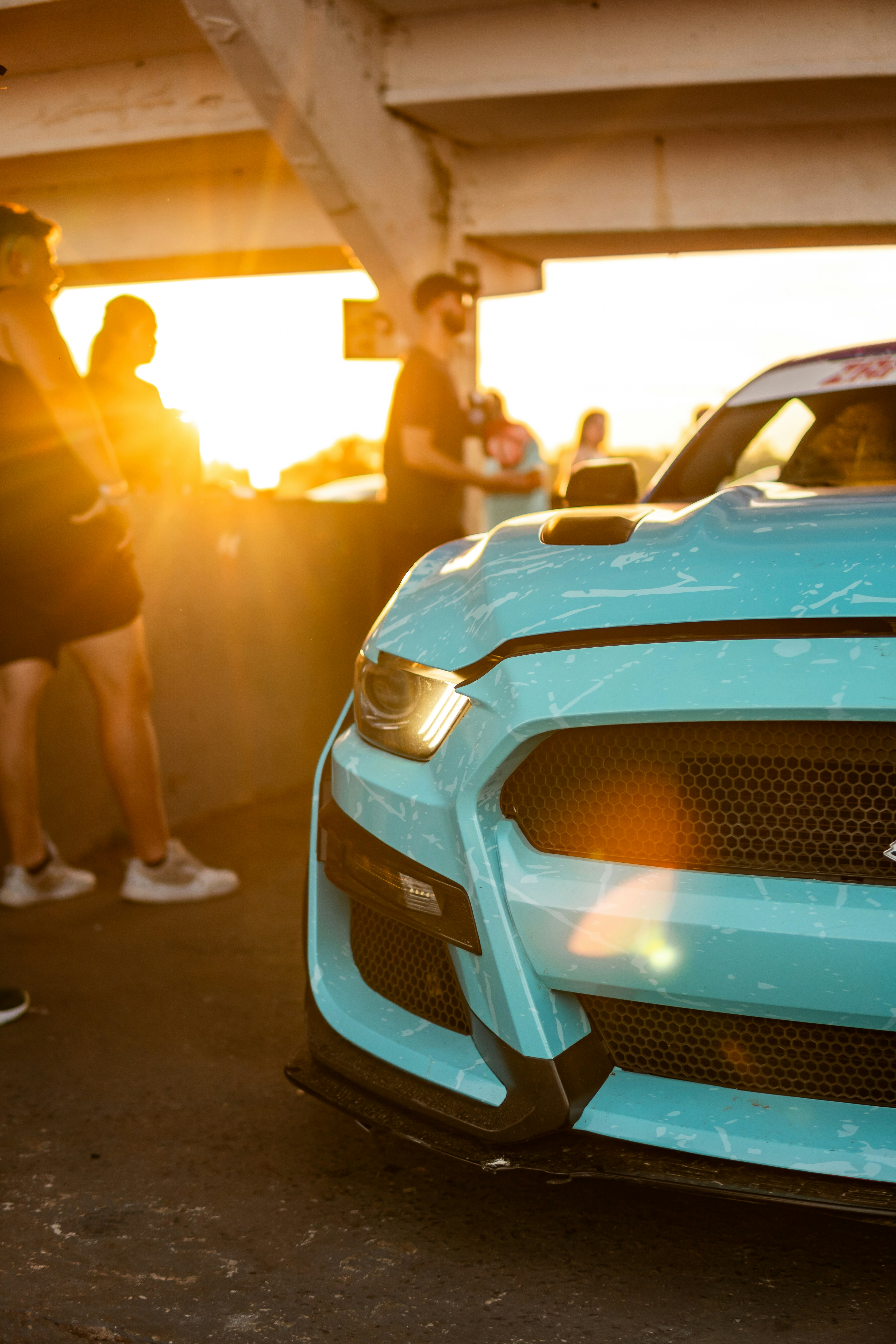Turquoise Iron Beast Under Sunset: A Car and Crowd Moment