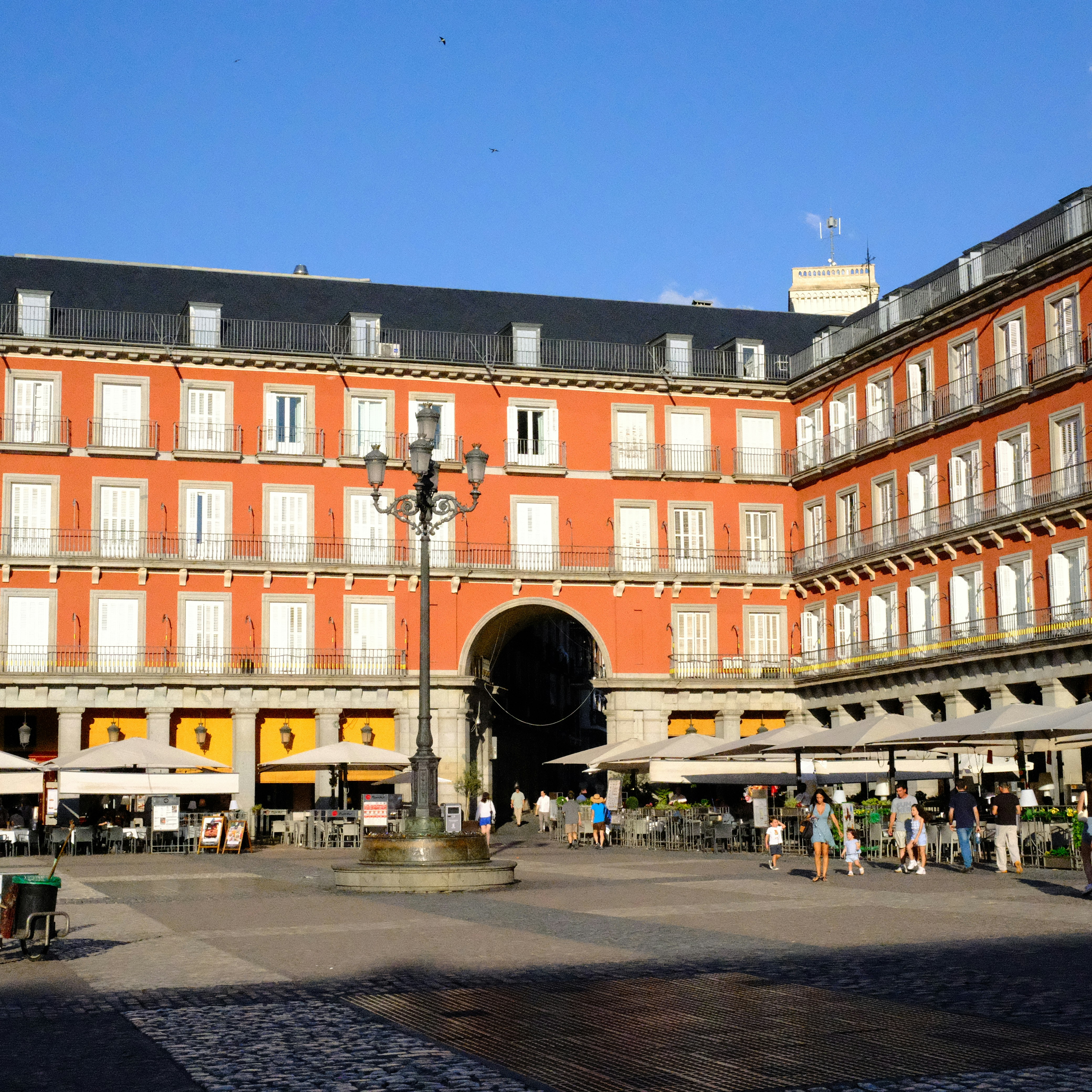 Civic Arc: A Sunlit Plaza Framed by Red-Orange Facades