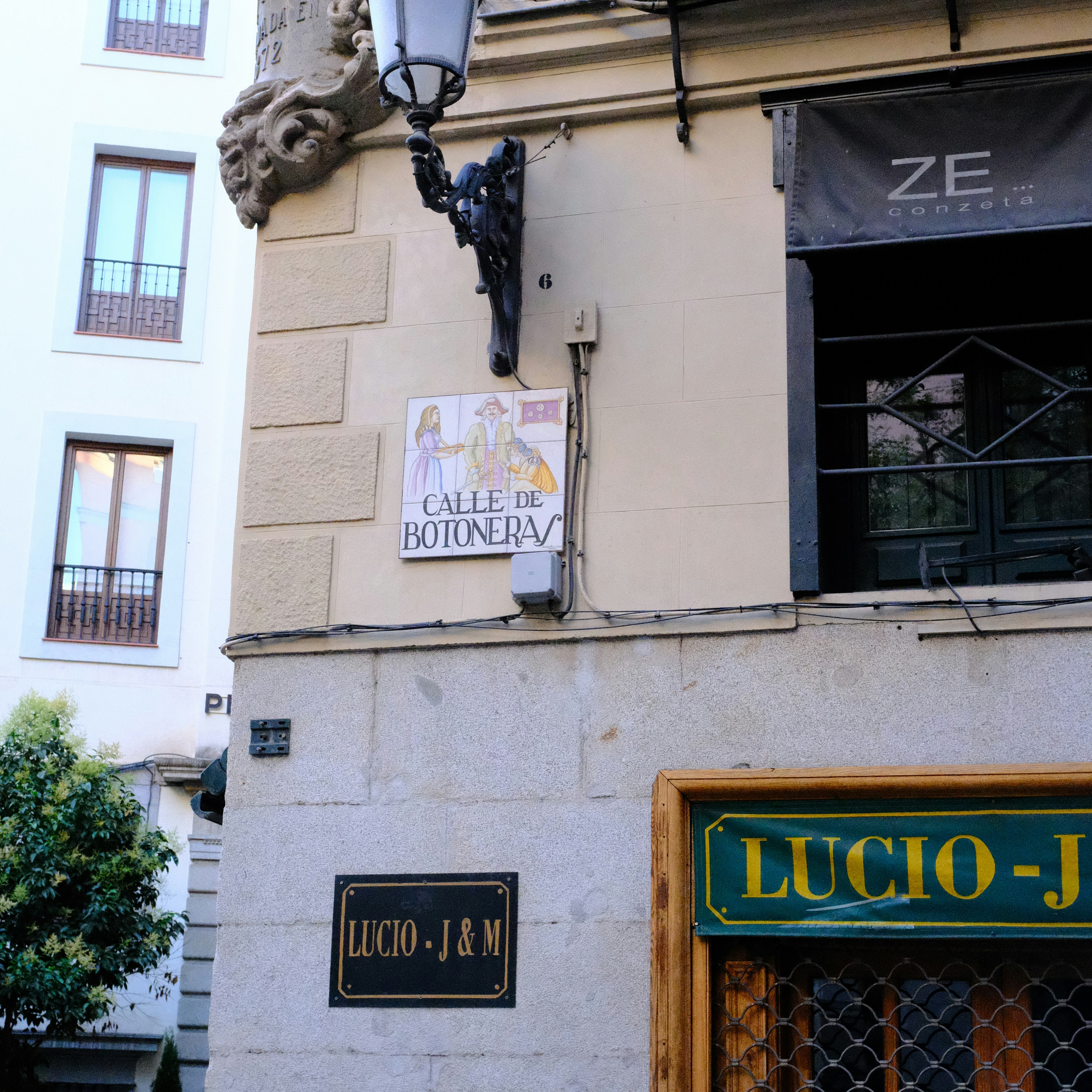 Signage and storefronts on a sunlit European street corner