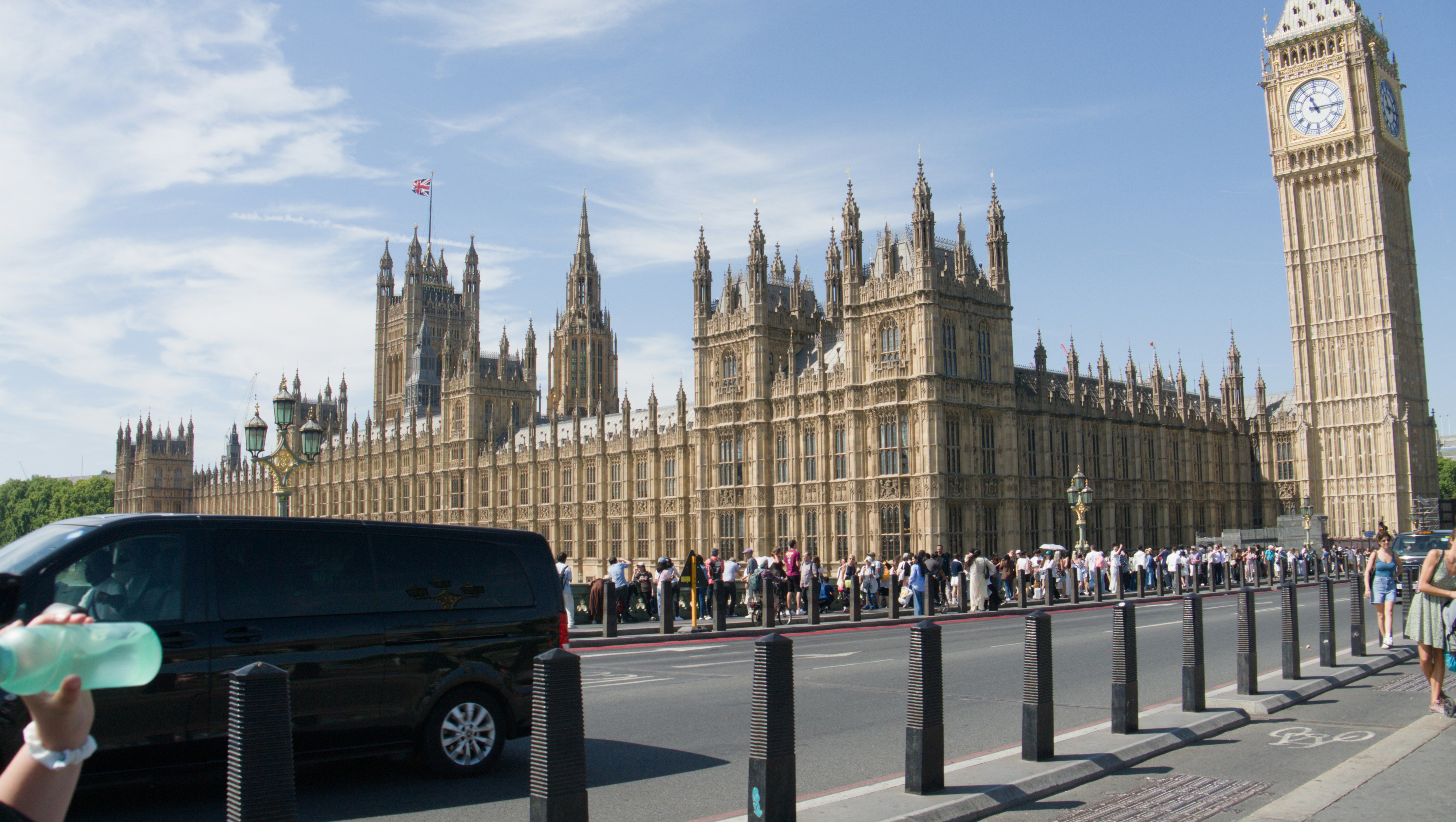 Towered Parliament: People, Bus, and Clock Tower under a Clear Sky
