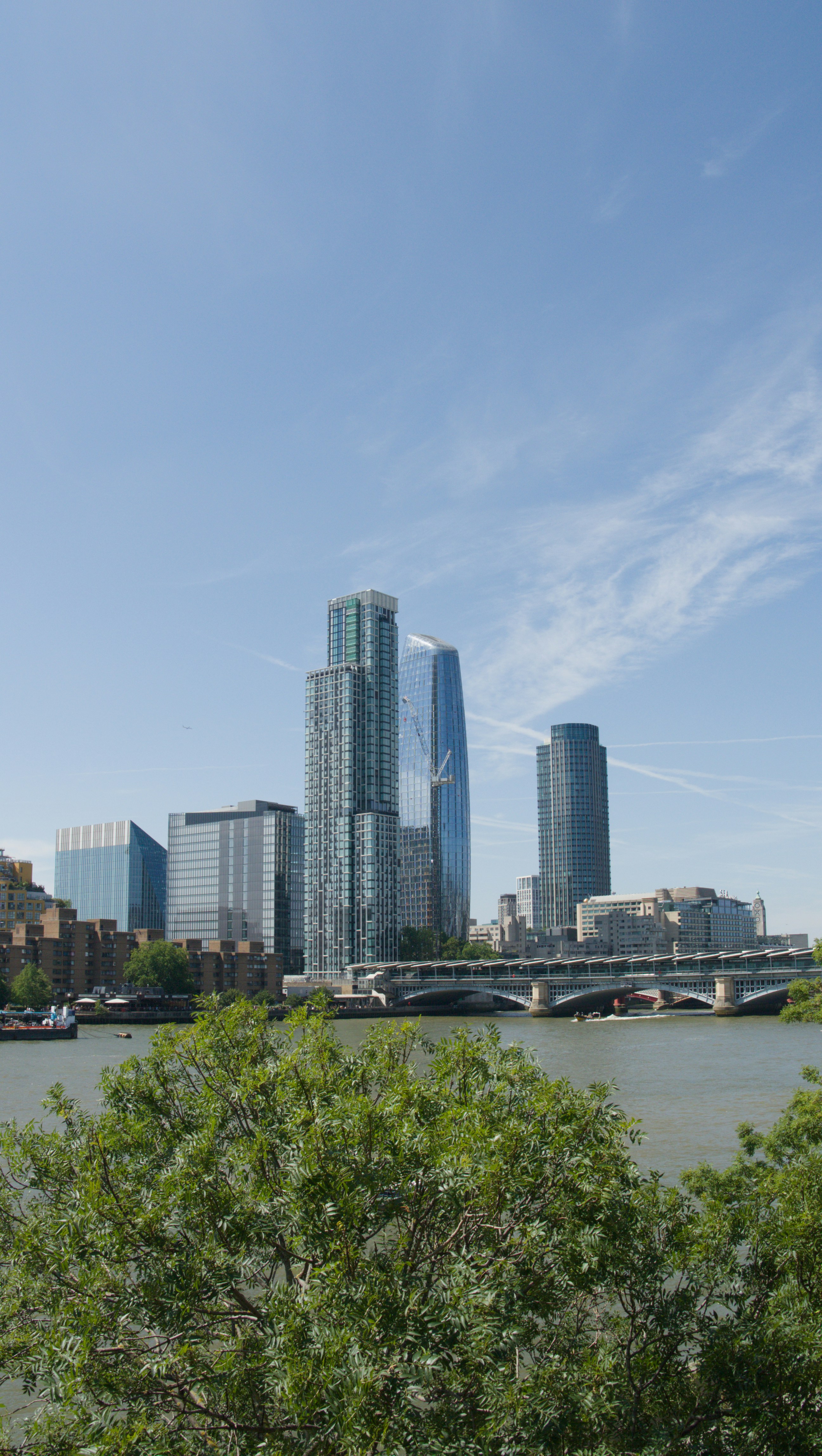 Urban Cascade: Glass Towers Rise Over the Thames-like Broad River