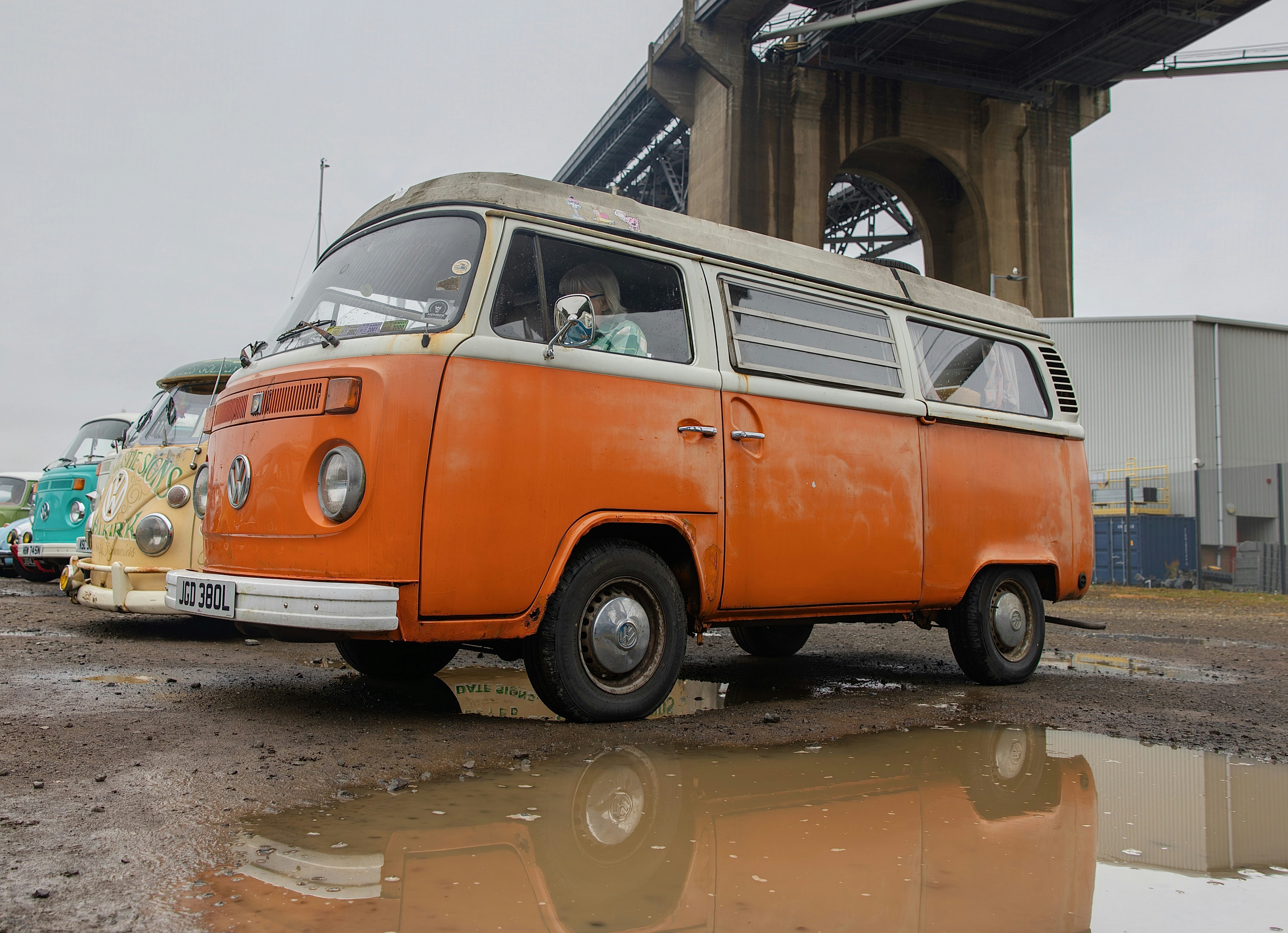 Orange VW Van at Riverside Rally under a Concrete Bridge