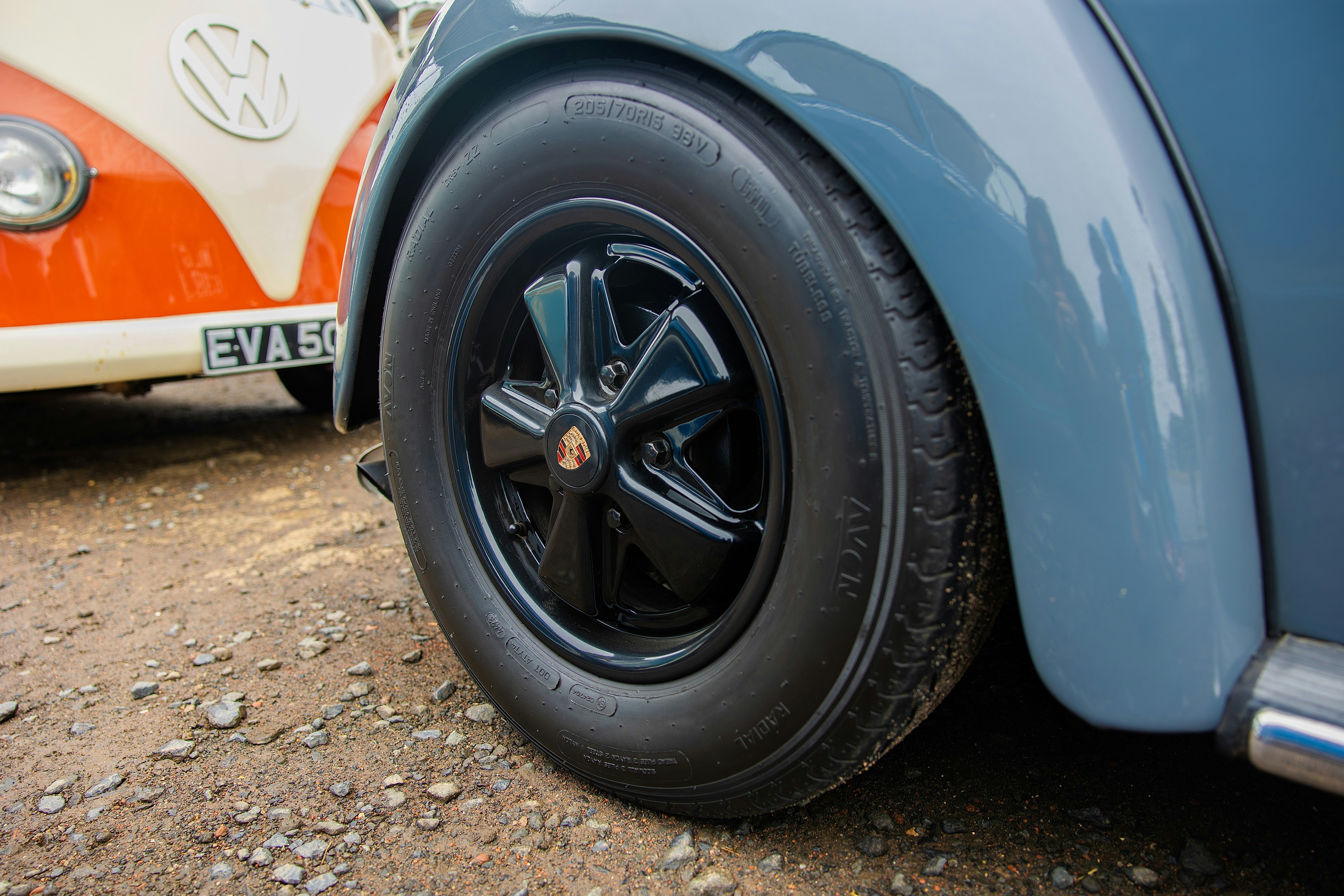 Blue Vintage Wheel with Black Hubcap Beside an Orange-White Classic