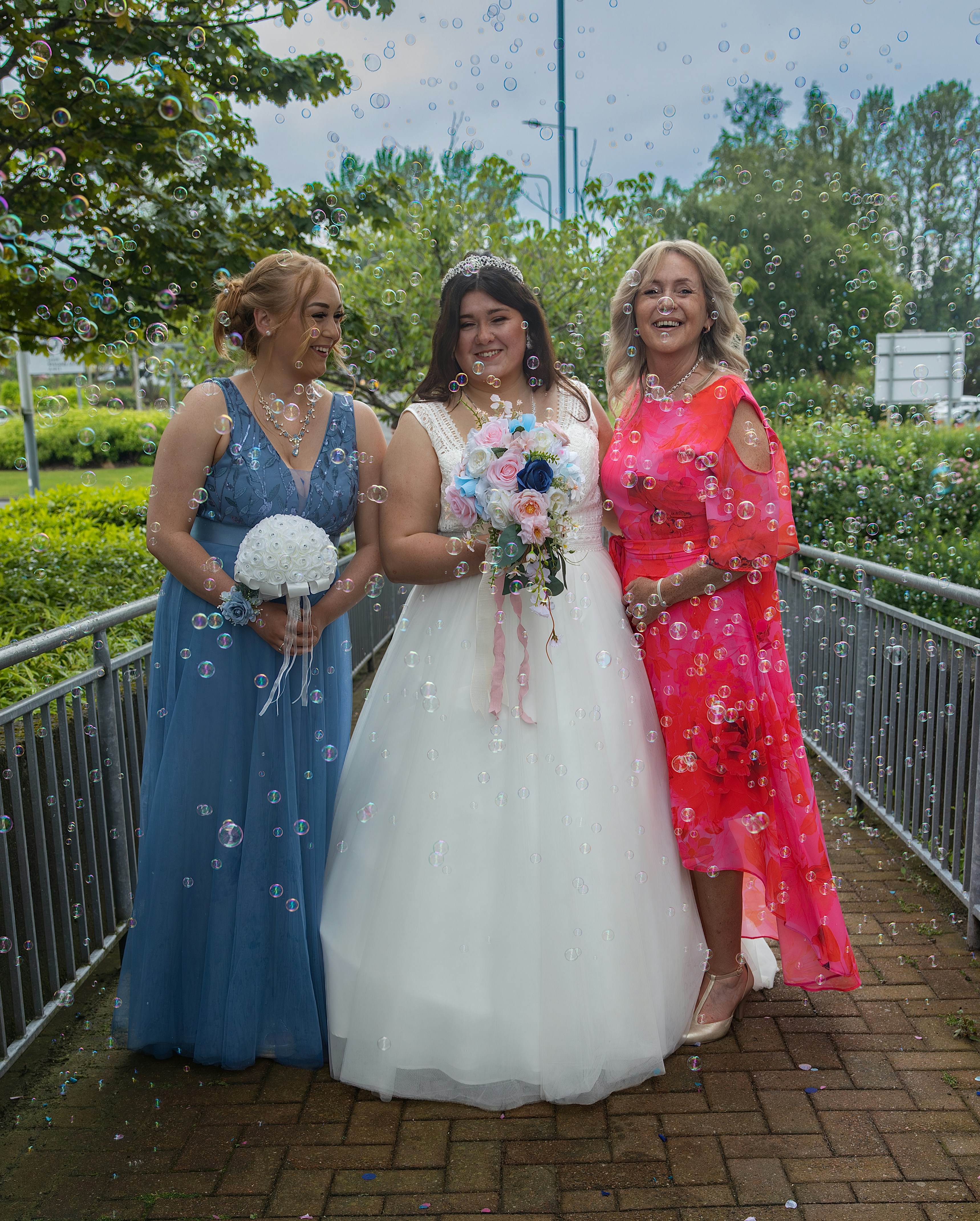 Bridesmaids and Bride Beneath Floating Bubbles on a Garden Path